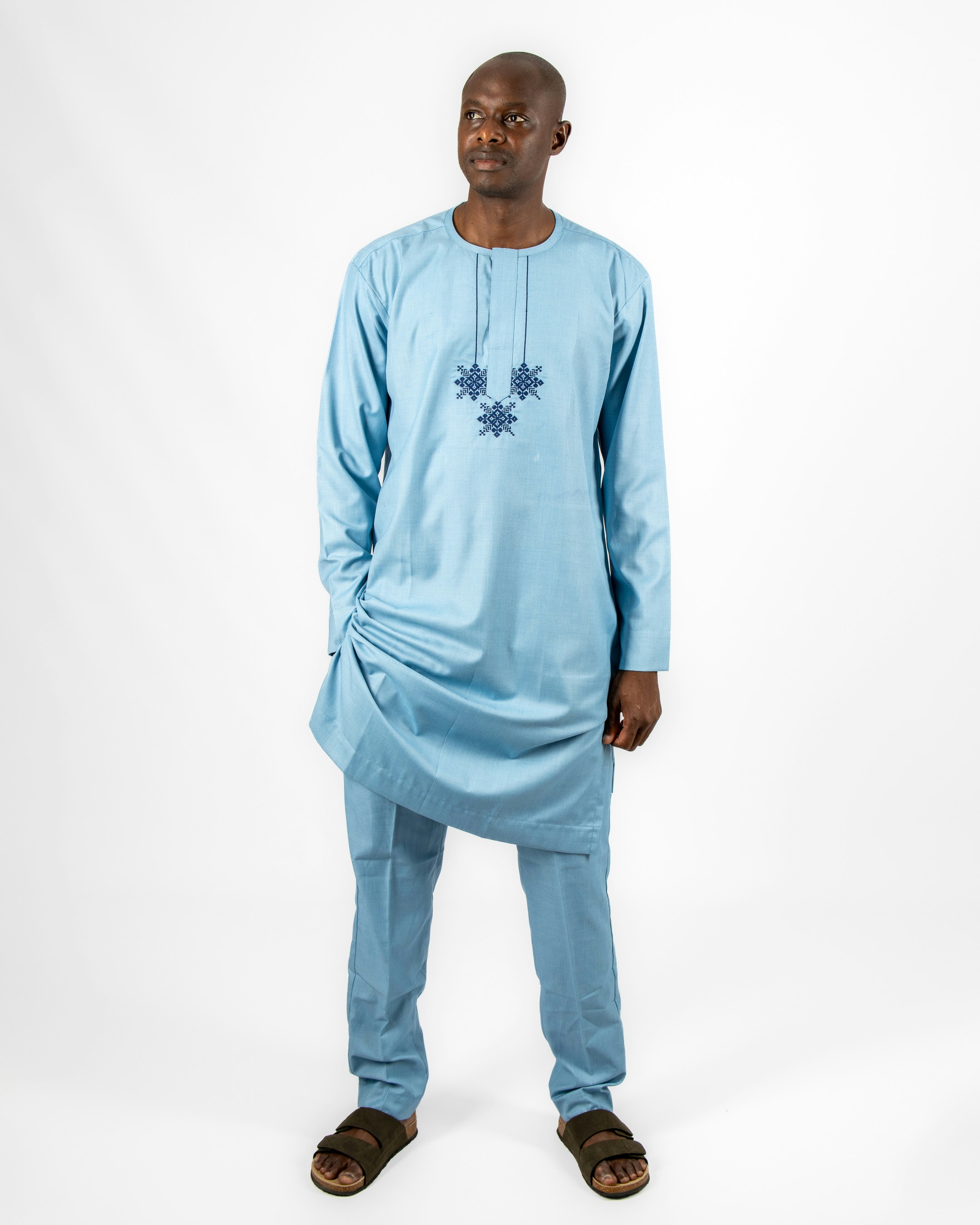 A man in a blue outfit standing in front of a white background