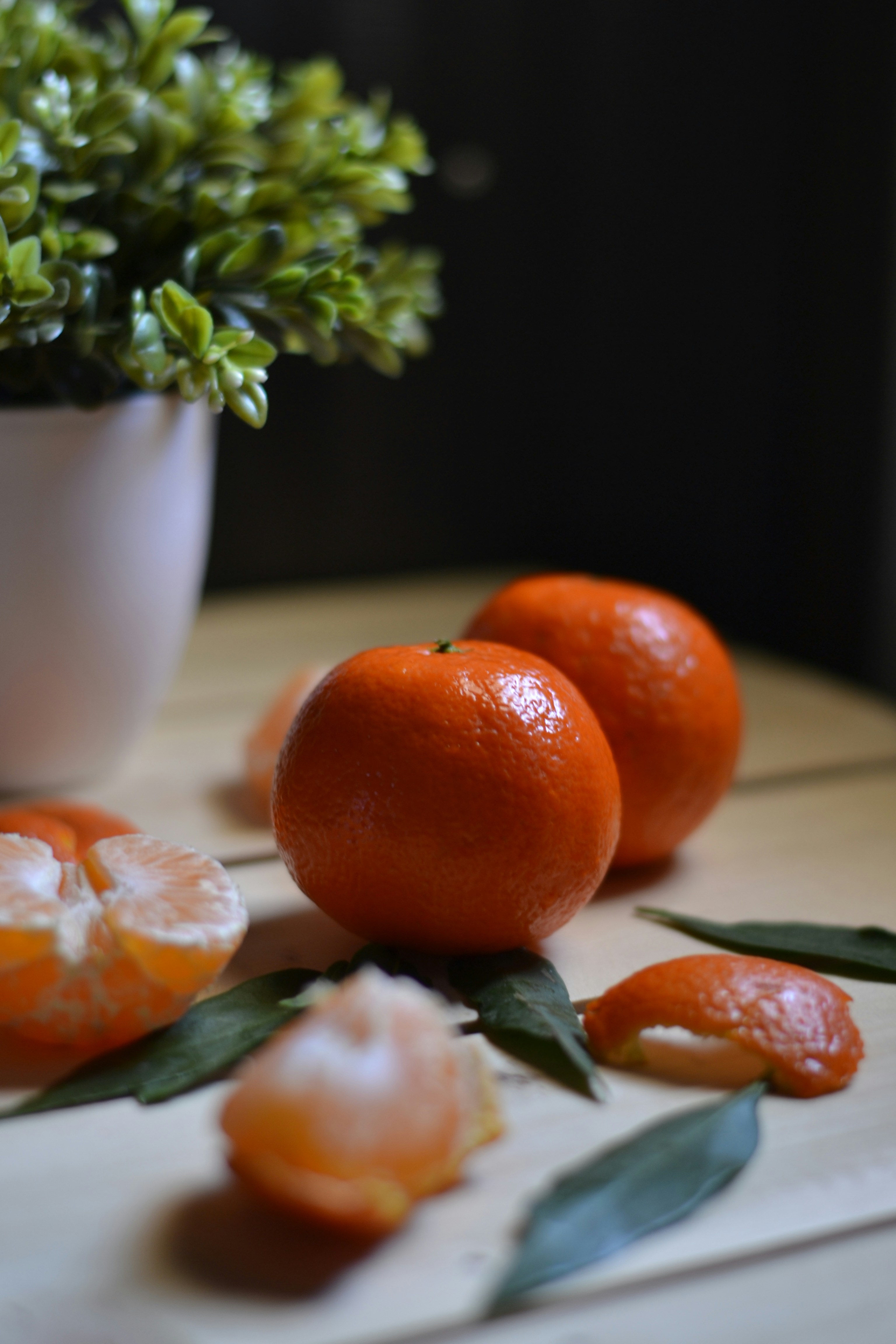 Un grupo de naranjas sentadas en una mesa junto a una planta en maceta ...