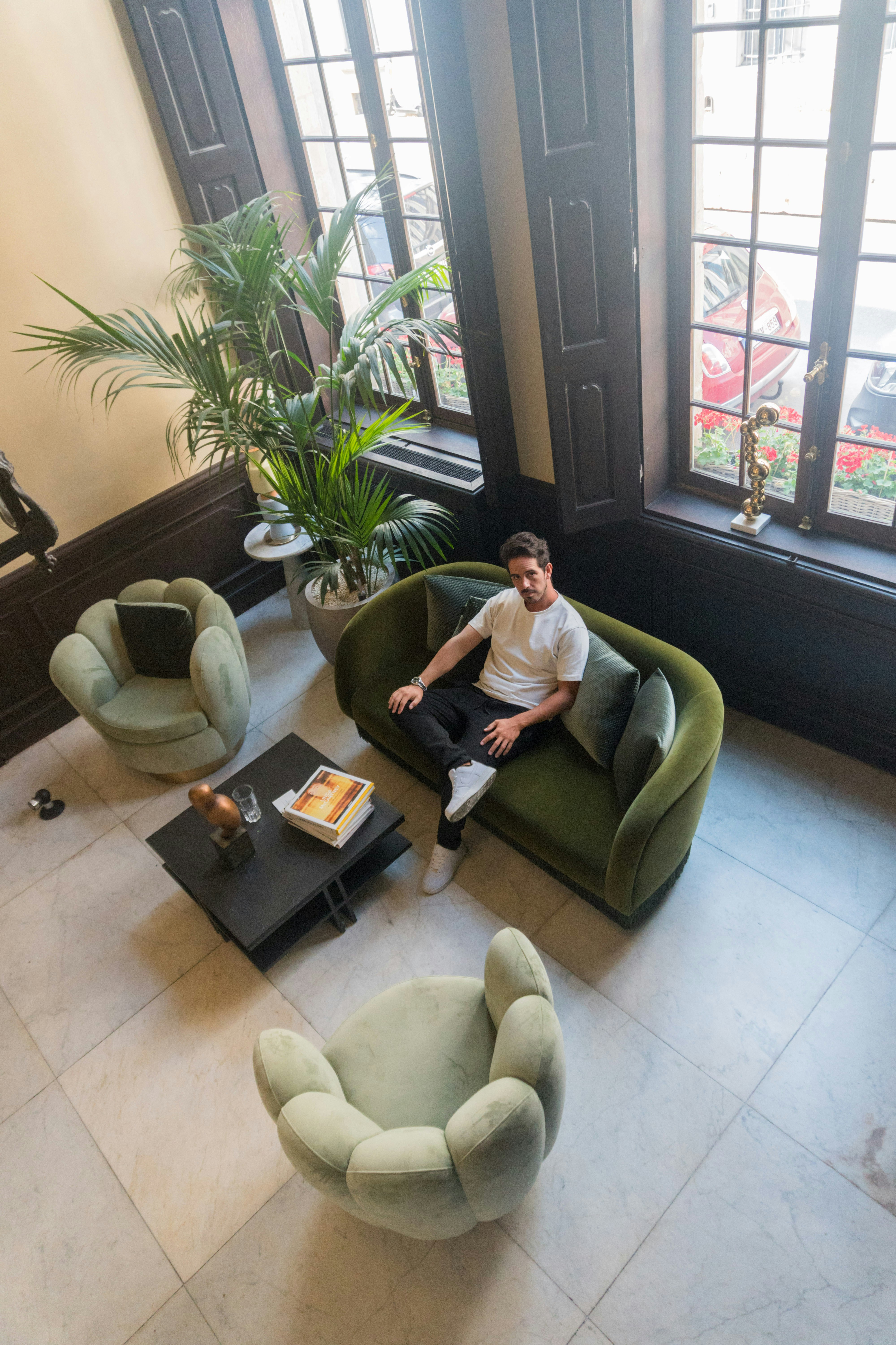 Comfort in a Sunlit Atrium: A Quiet Moment on the Green Sofa