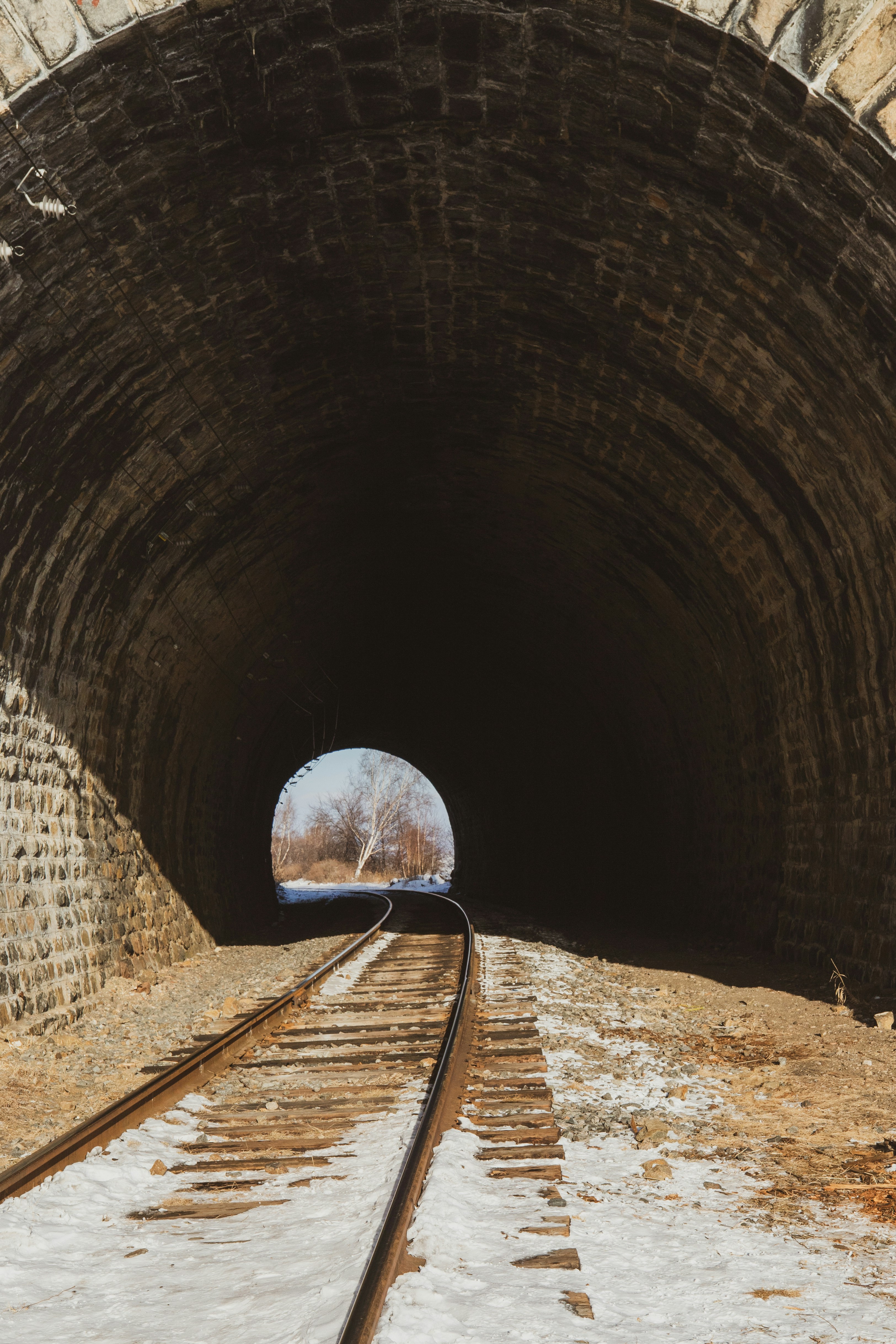 Une voie ferrée entrant dans un tunnel avec de la neige au sol photo ...