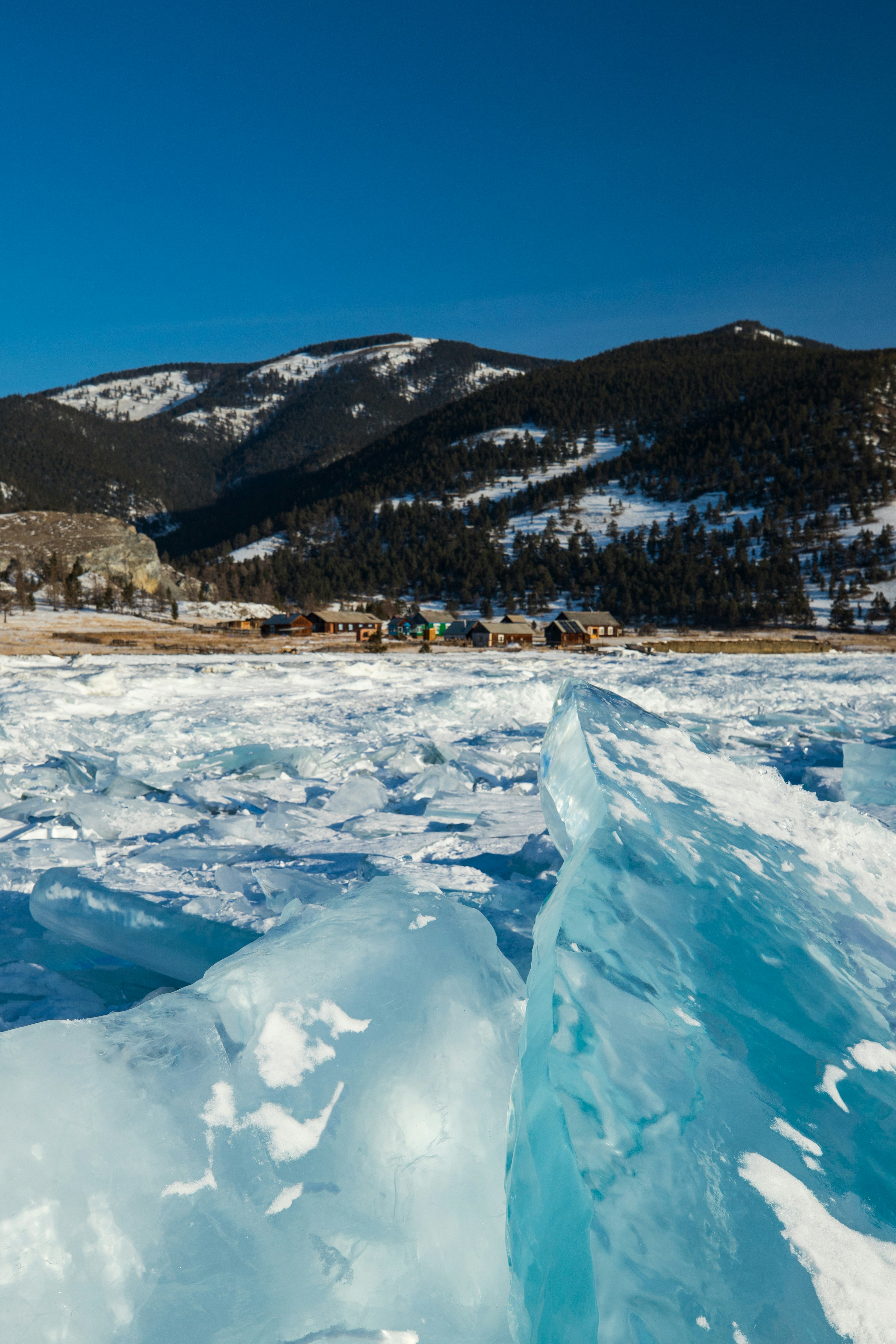 Glacial Cerulean Break: Jagged Ice Against a Mountain Village