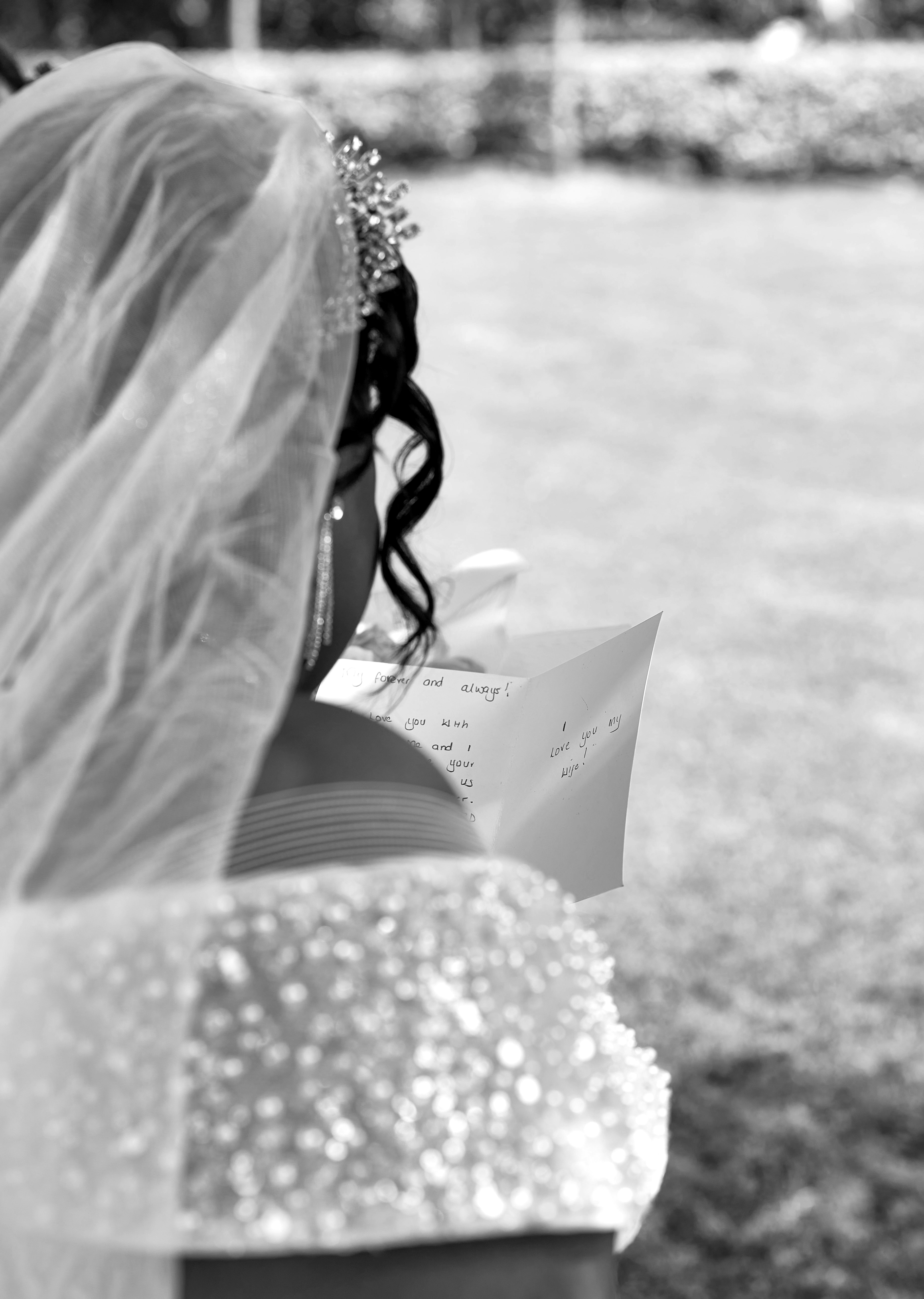 Veil and Letter: A Bride Reads a Folded Note on a Sunlit Lawn