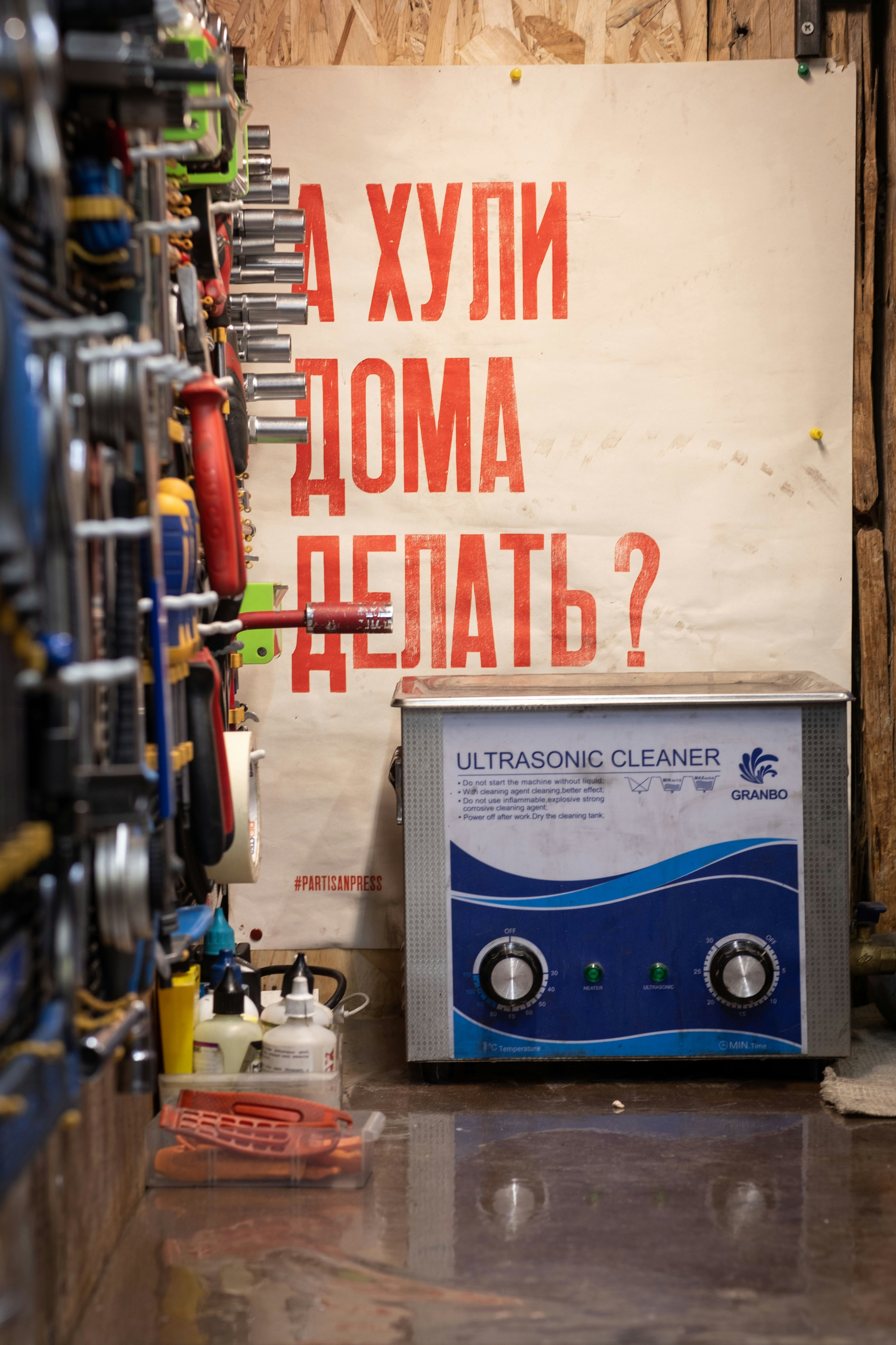 Blue Ultrasonic Cleaner Guards a Tool Rack in a Noisy Workshop