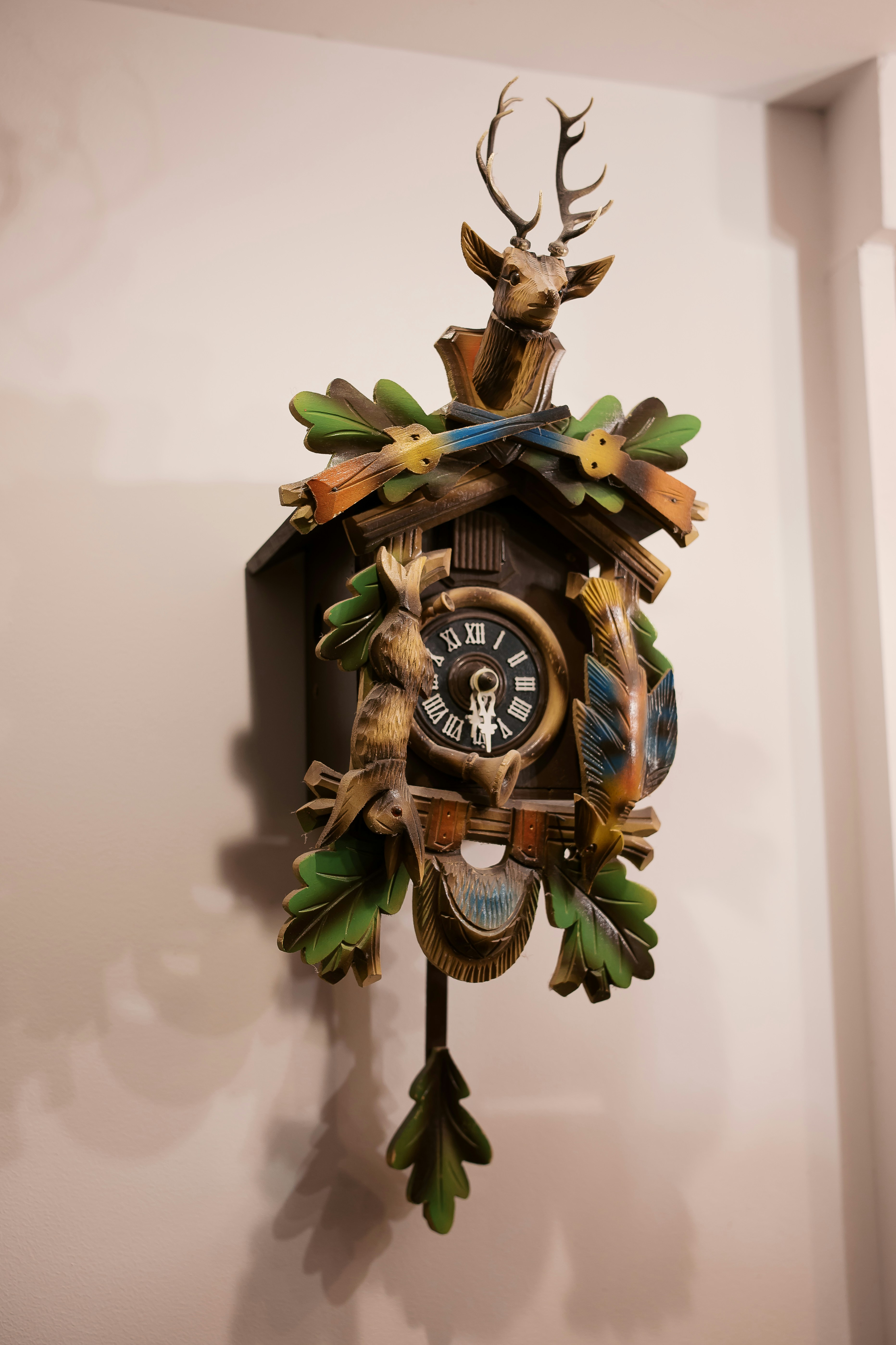 Cuckoo Clock Portrait: Deer Crest and Leaf Carvings in Warm Hallway Light
