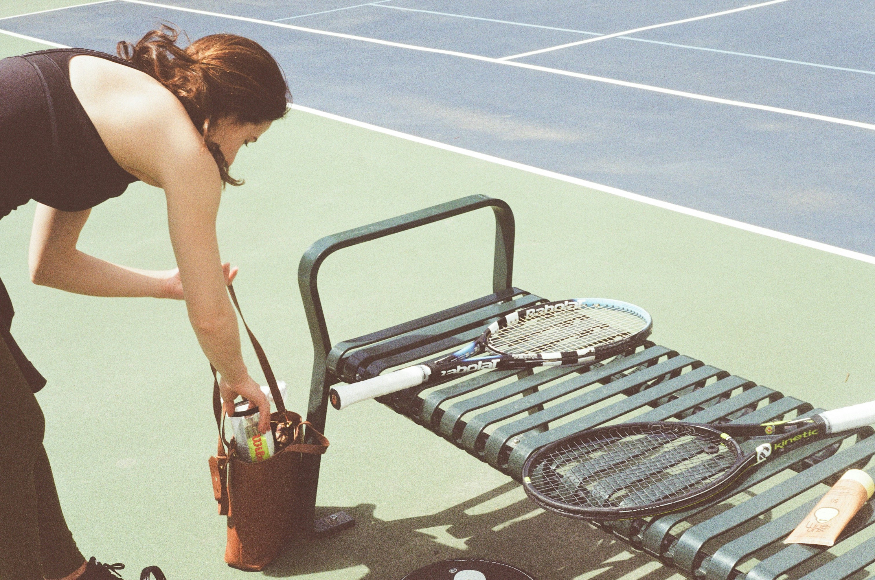 A woman bending over to pick up a tennis racket photo – Free Us open ...