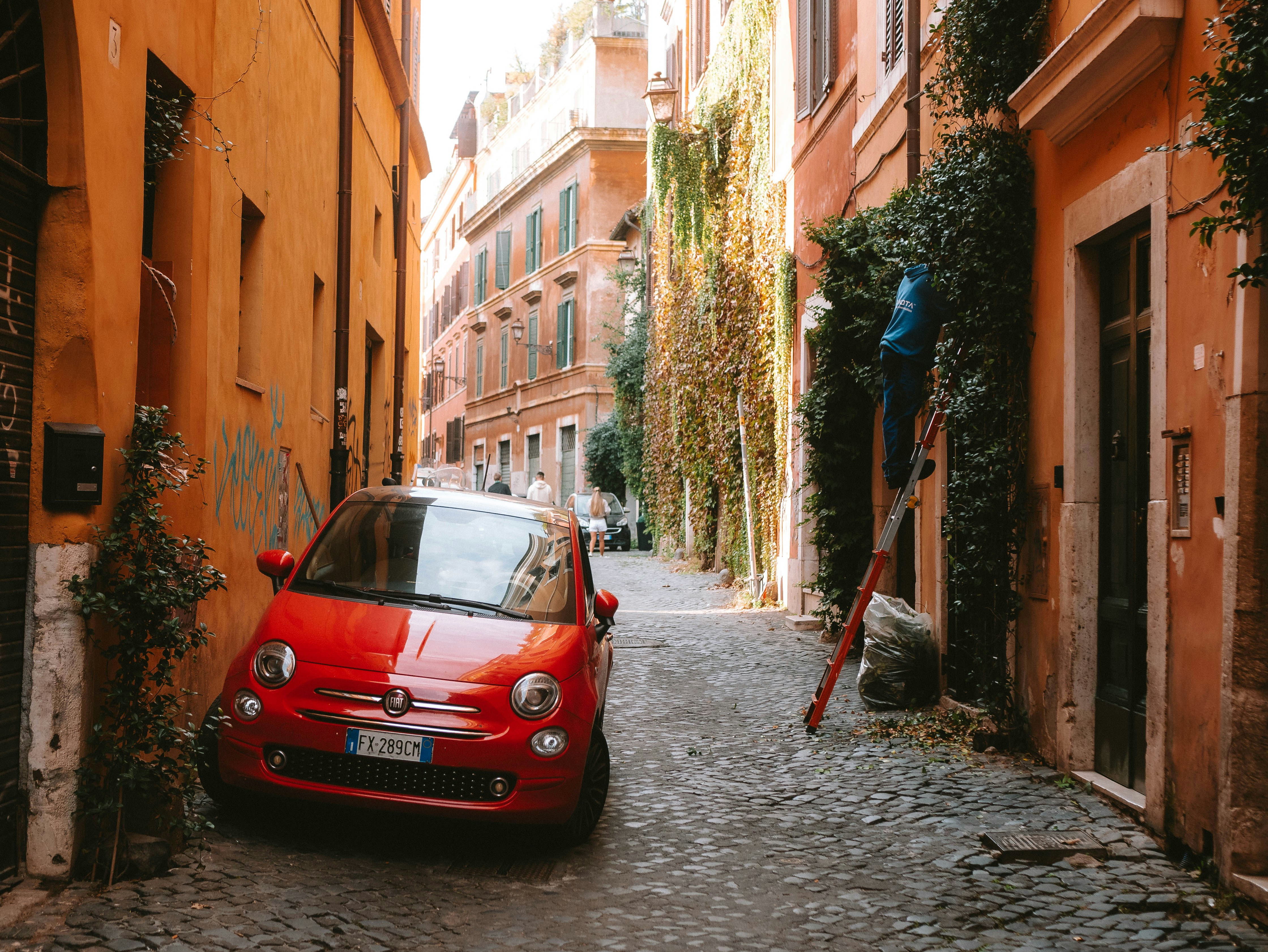 Crimson Fiat in a Sunlit Italian Alley