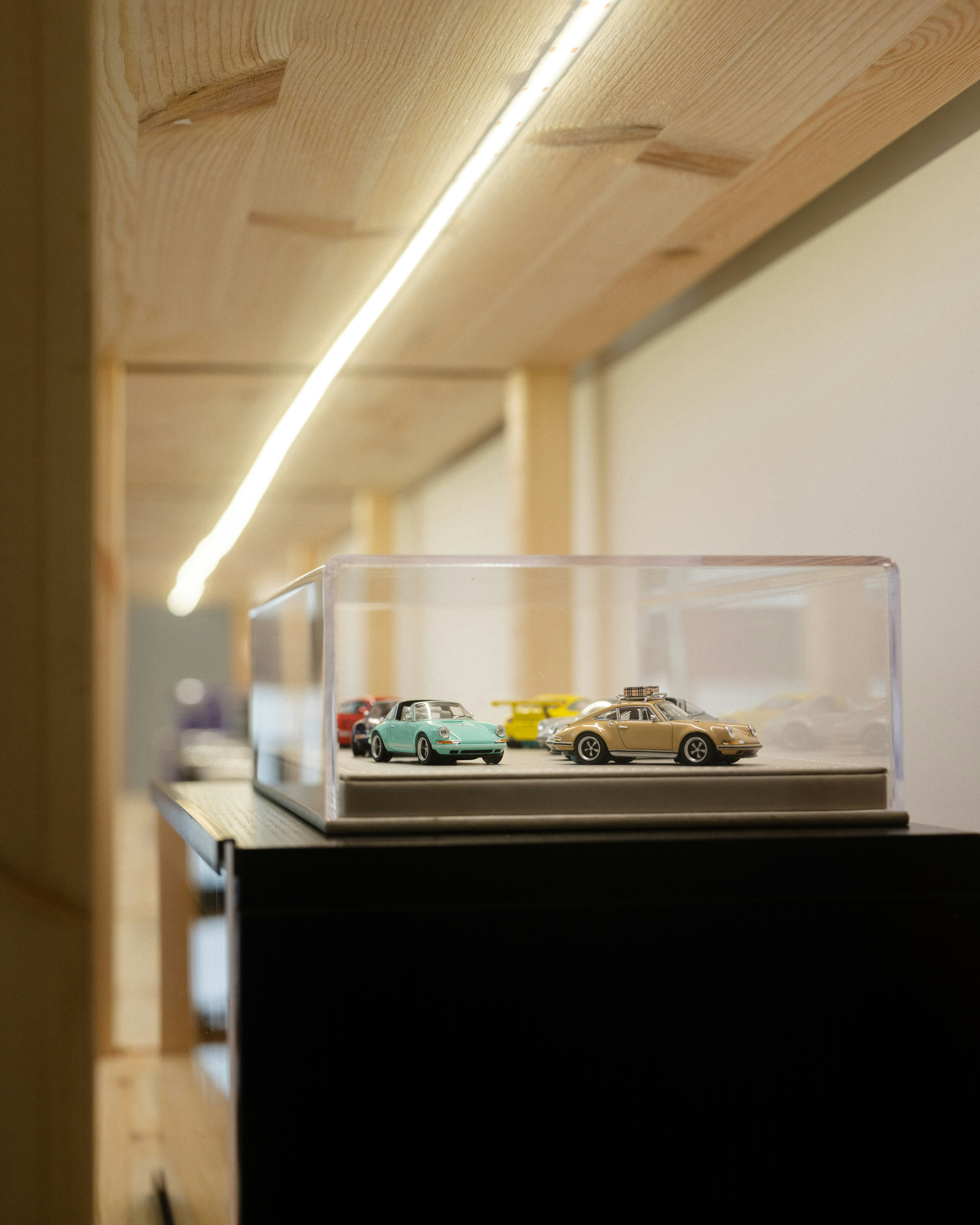 Glass-Case Miniature Car Gallery Under Warm Studio Light