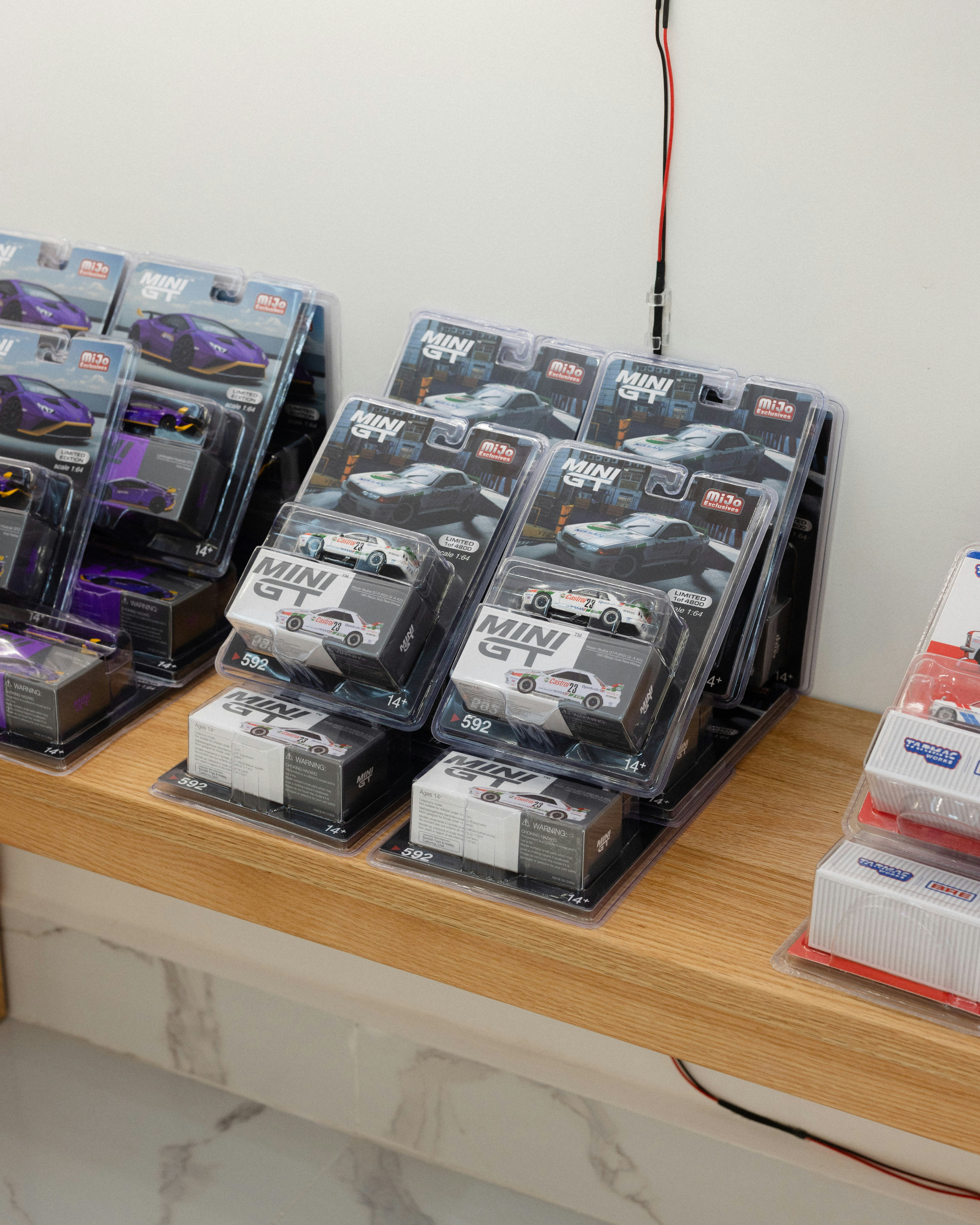 Stacked Mini GT Die-Cast Parade on a Wooden Shelf