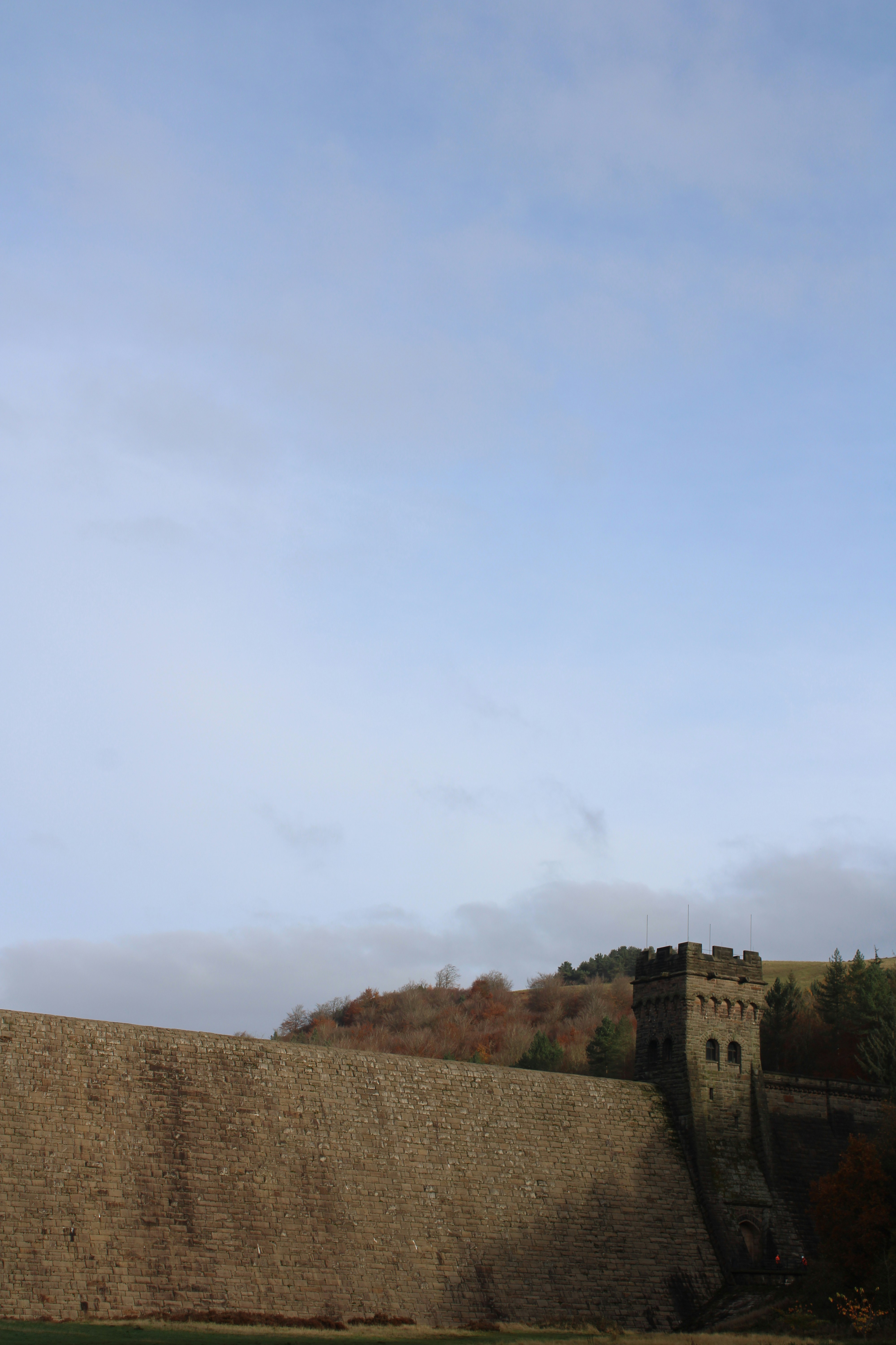A large stone wall with a clock tower in the background