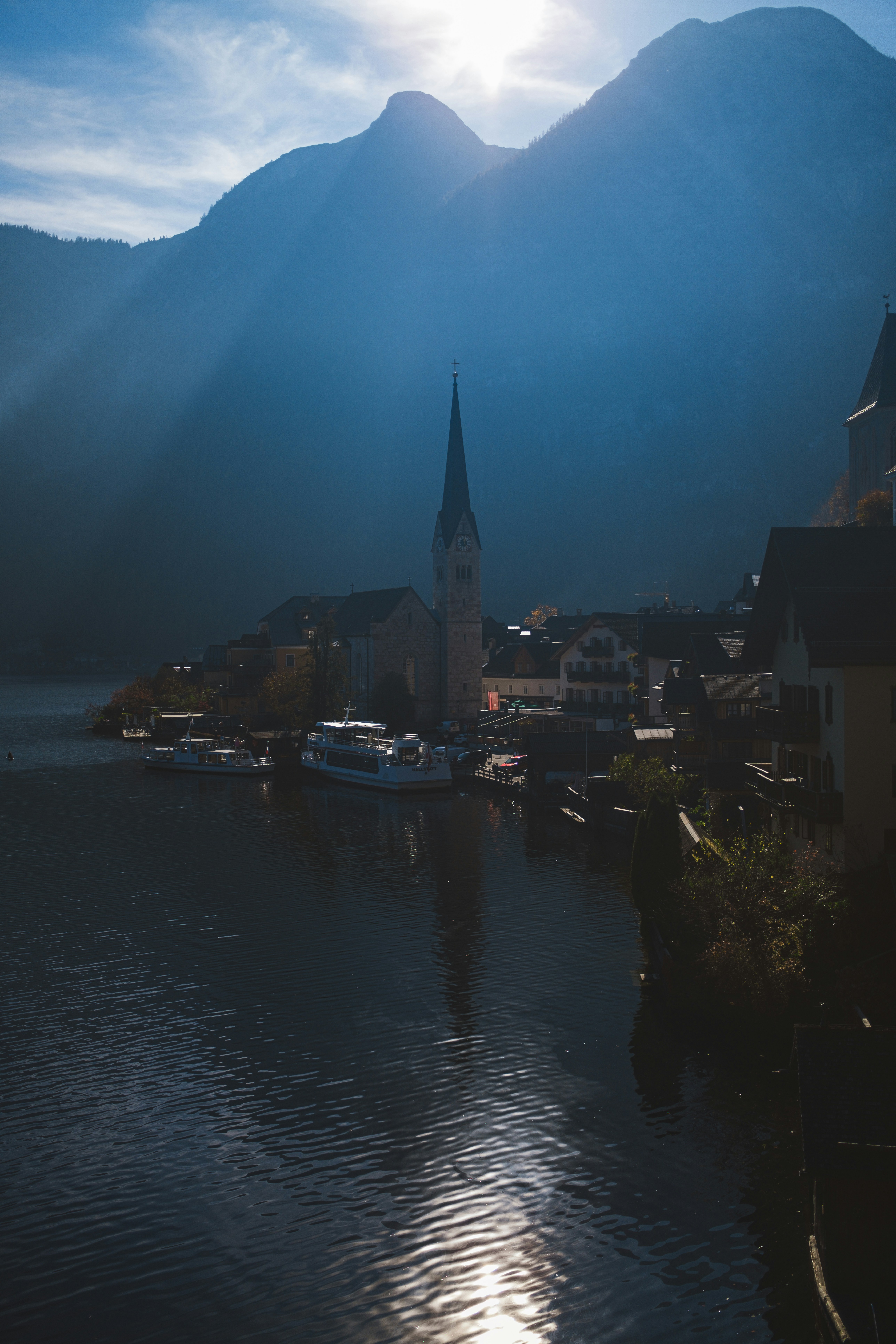 Dawn over a Lakeside Alpine Village: The Spire Silhouette against Misty Peaks