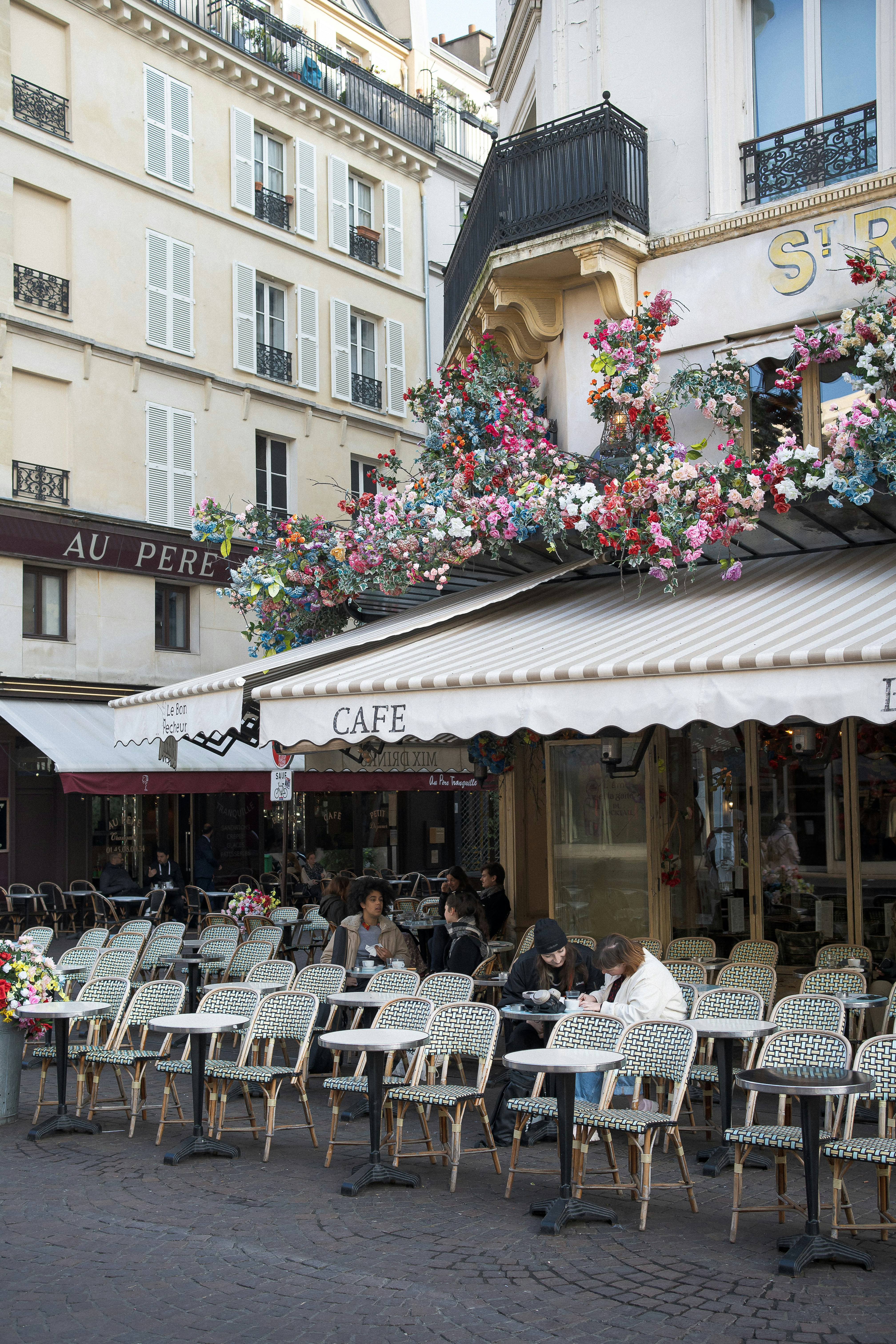Floral Canopy Over a Parisian Café Terrace on a Sunlit Street