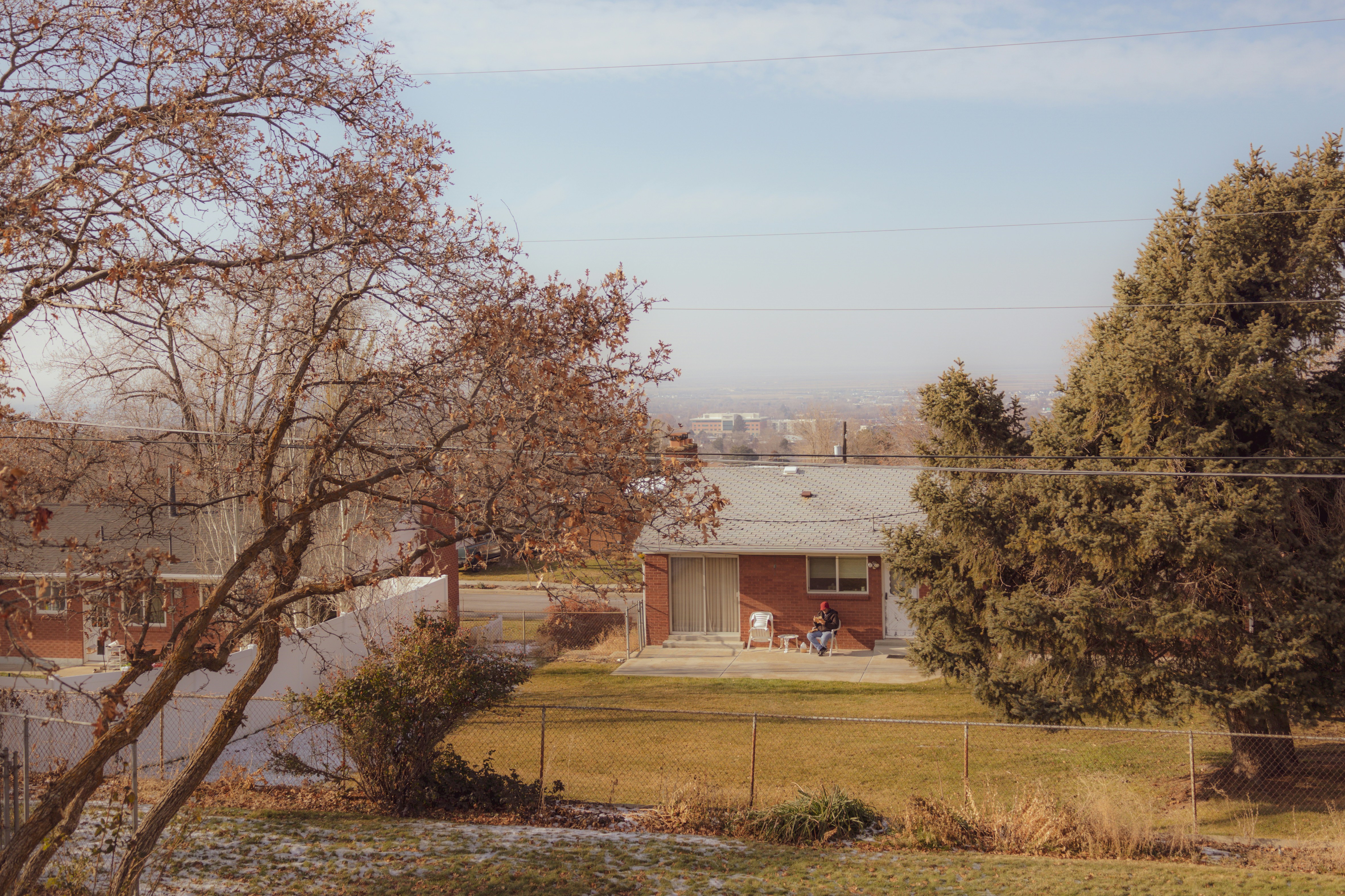 Suburban house with bare trees and a lawn under a clear blue sky in winter.