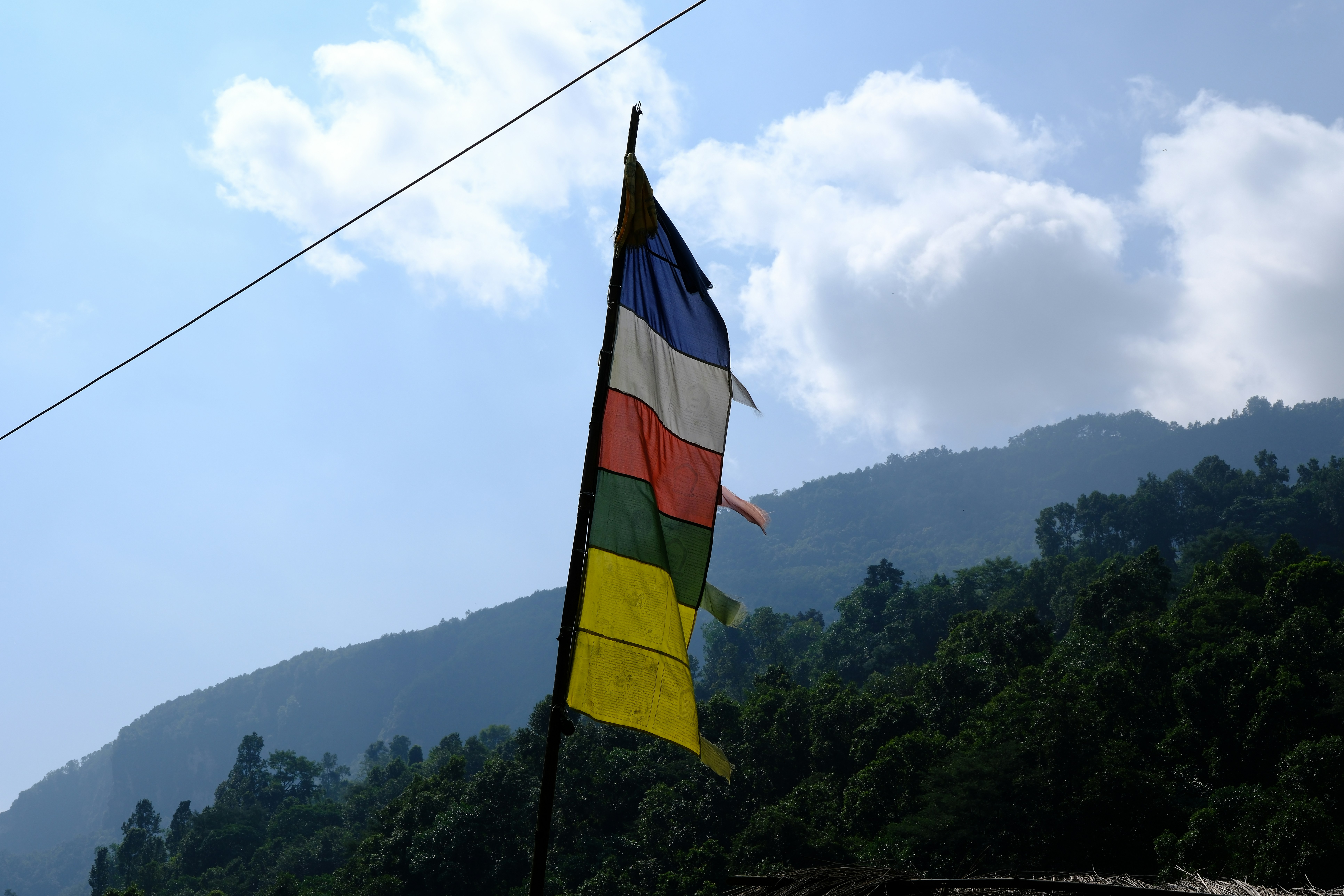 Five-Color Prayer Flag Drifting Over a Verdant Mountain Ridge