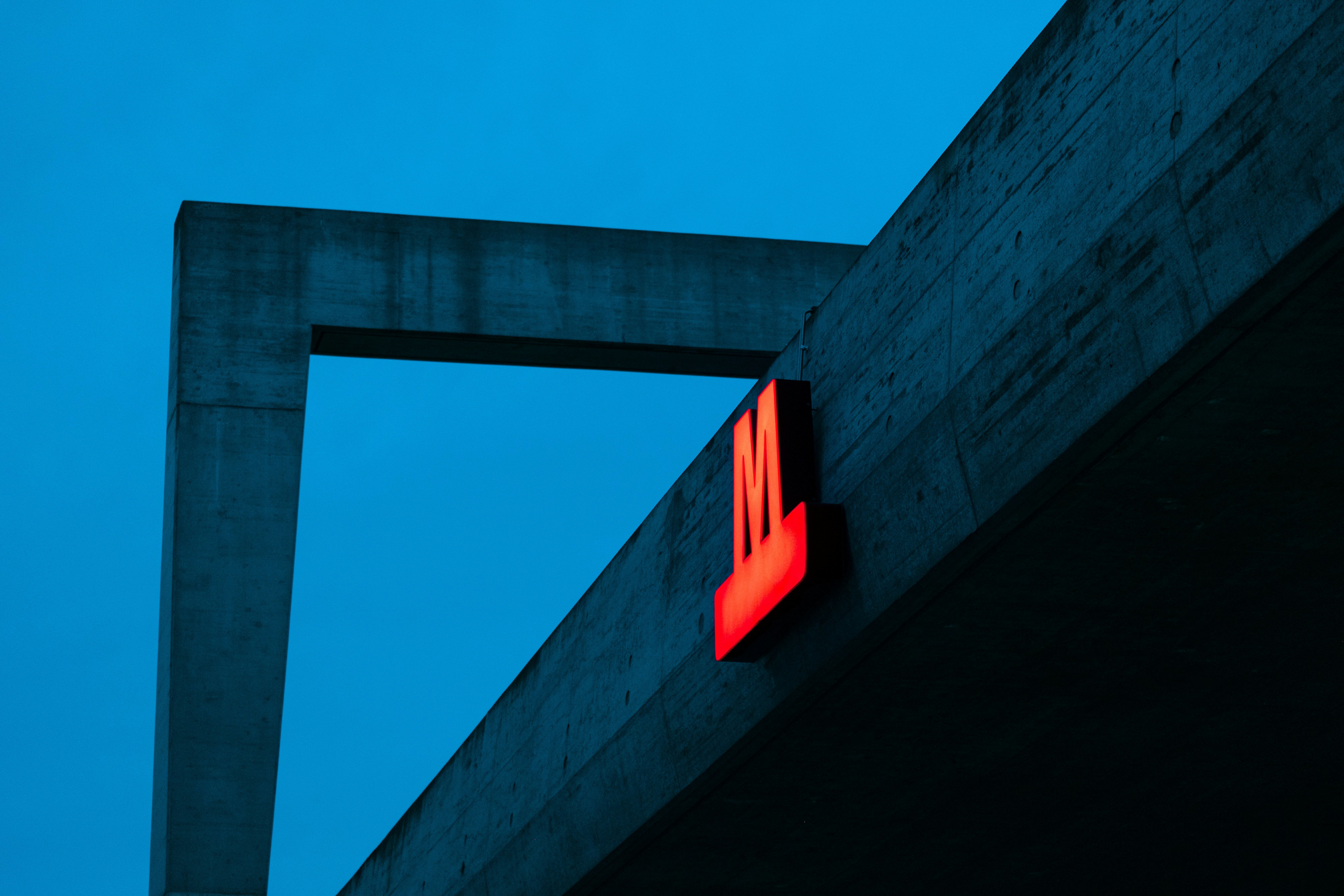 Crimson Neon M Framed by Blue Concrete