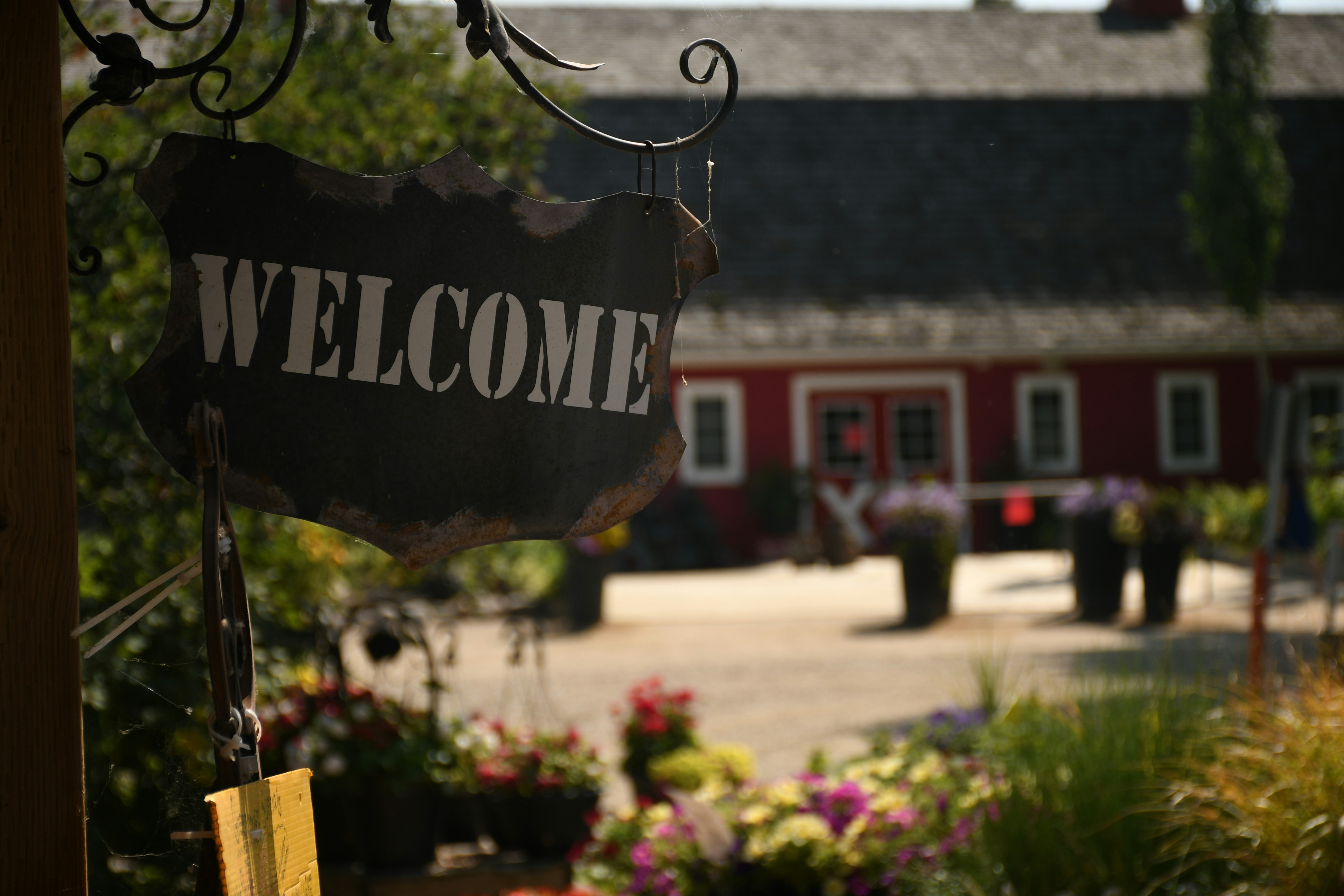 A welcome sign hanging from the side of a building photo – Free ...