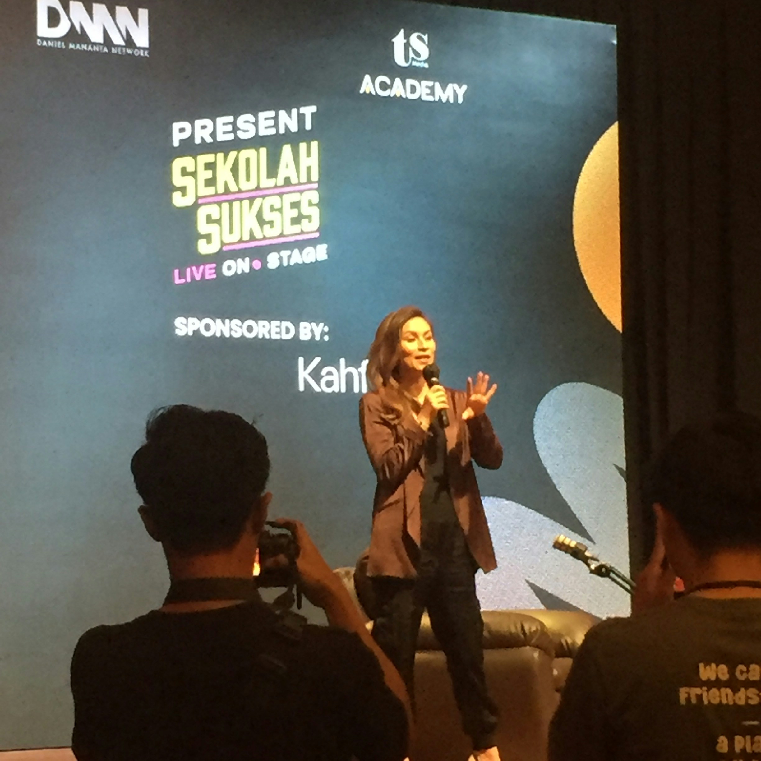 A woman standing on a stage speaking to a group of people photo – Free ...