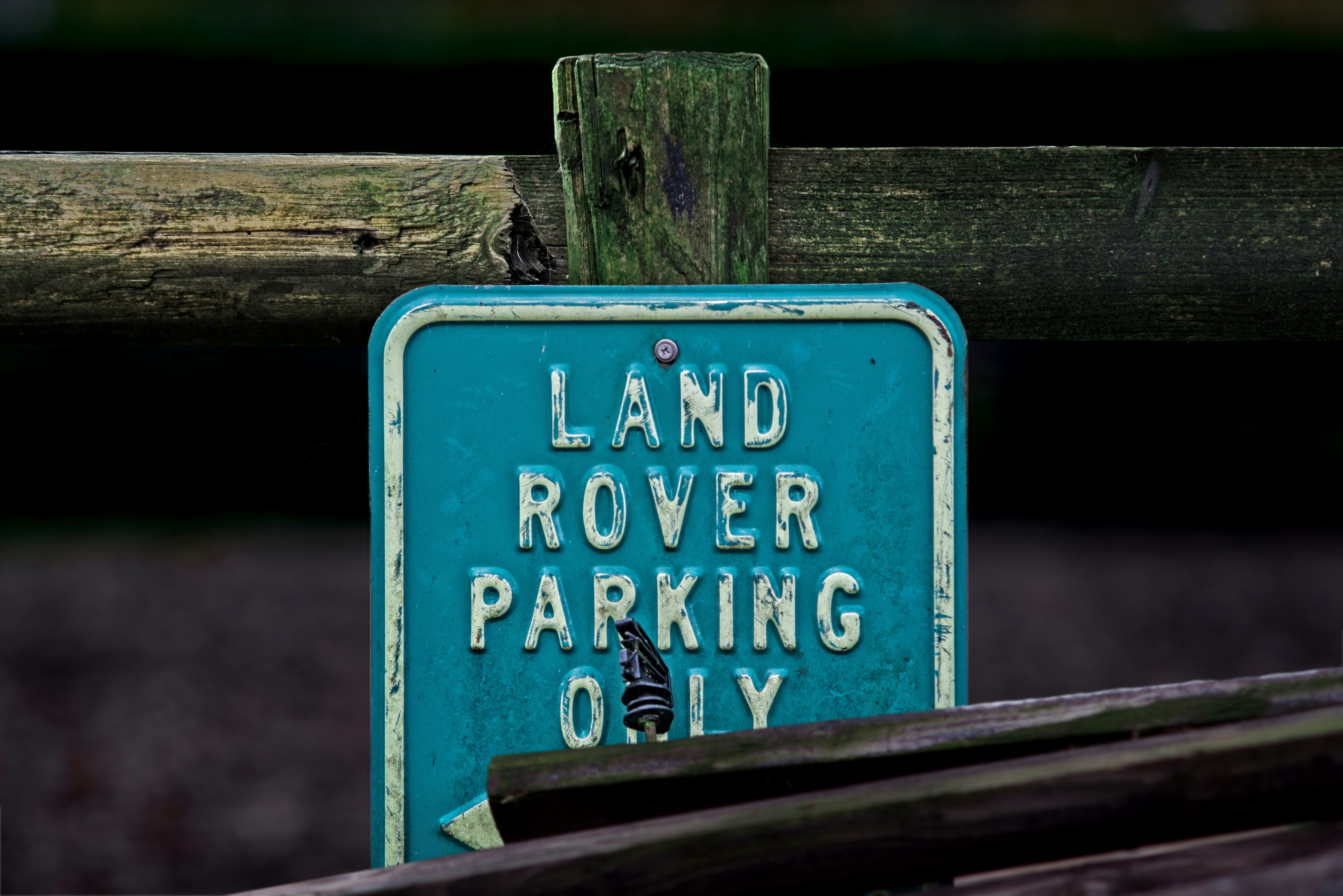 Weathered Blue Land Rover Parking Sign Framed by Rustic Wood