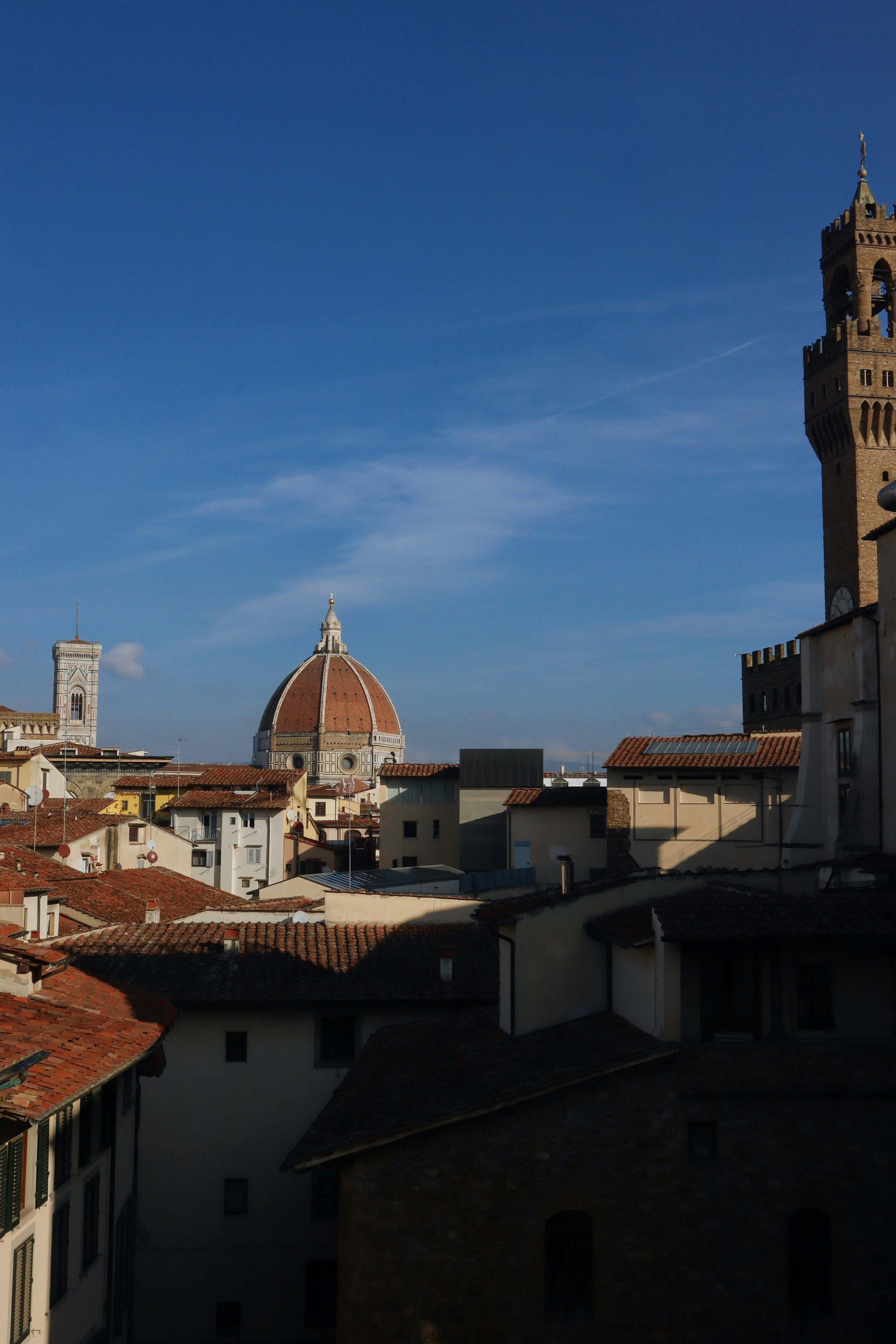 Florence's iconic dome and clock tower under a clear blue sky.