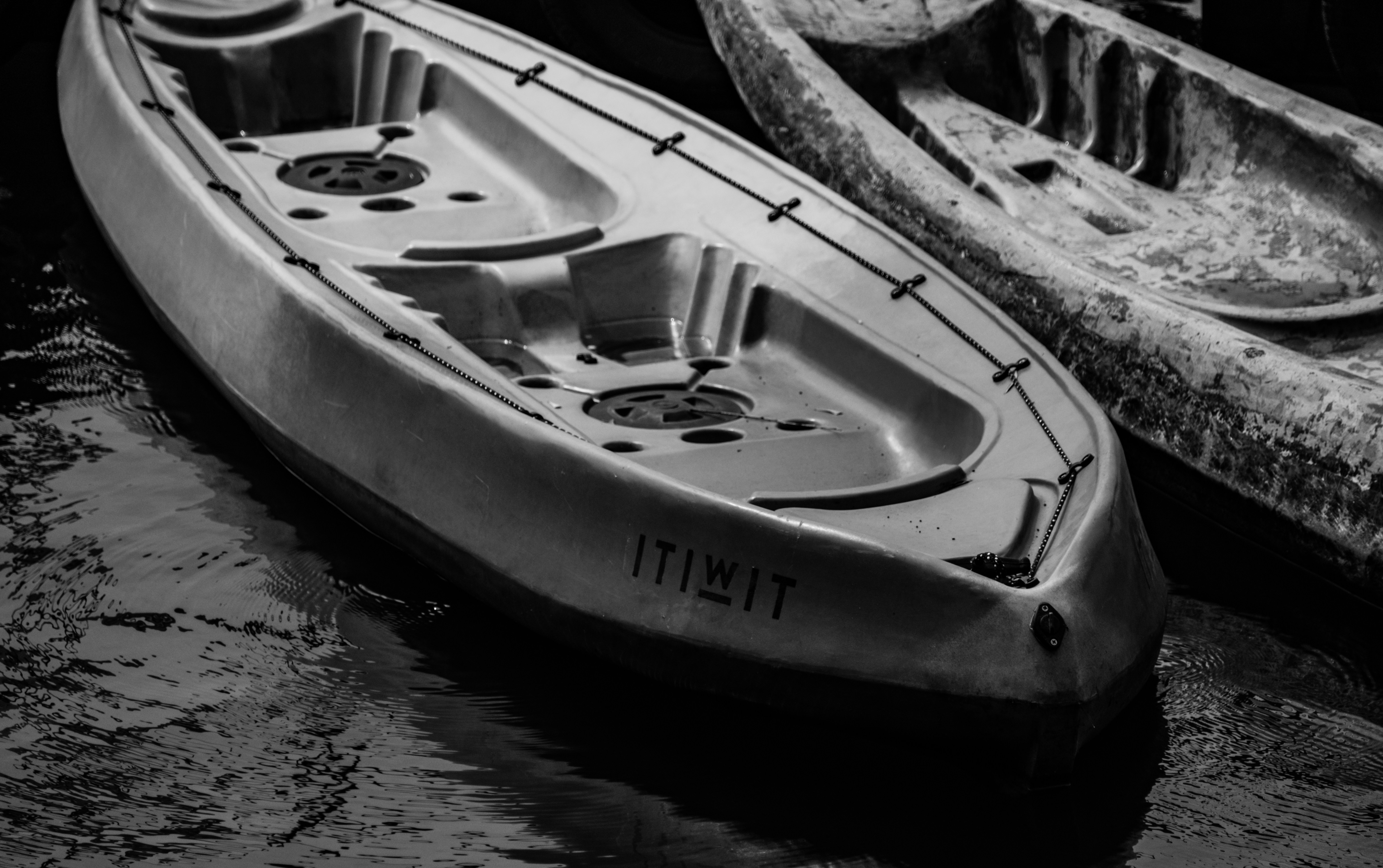 Monochrome Bow: A Weathered ITIWIT Kayak Resting in Shadowed Water