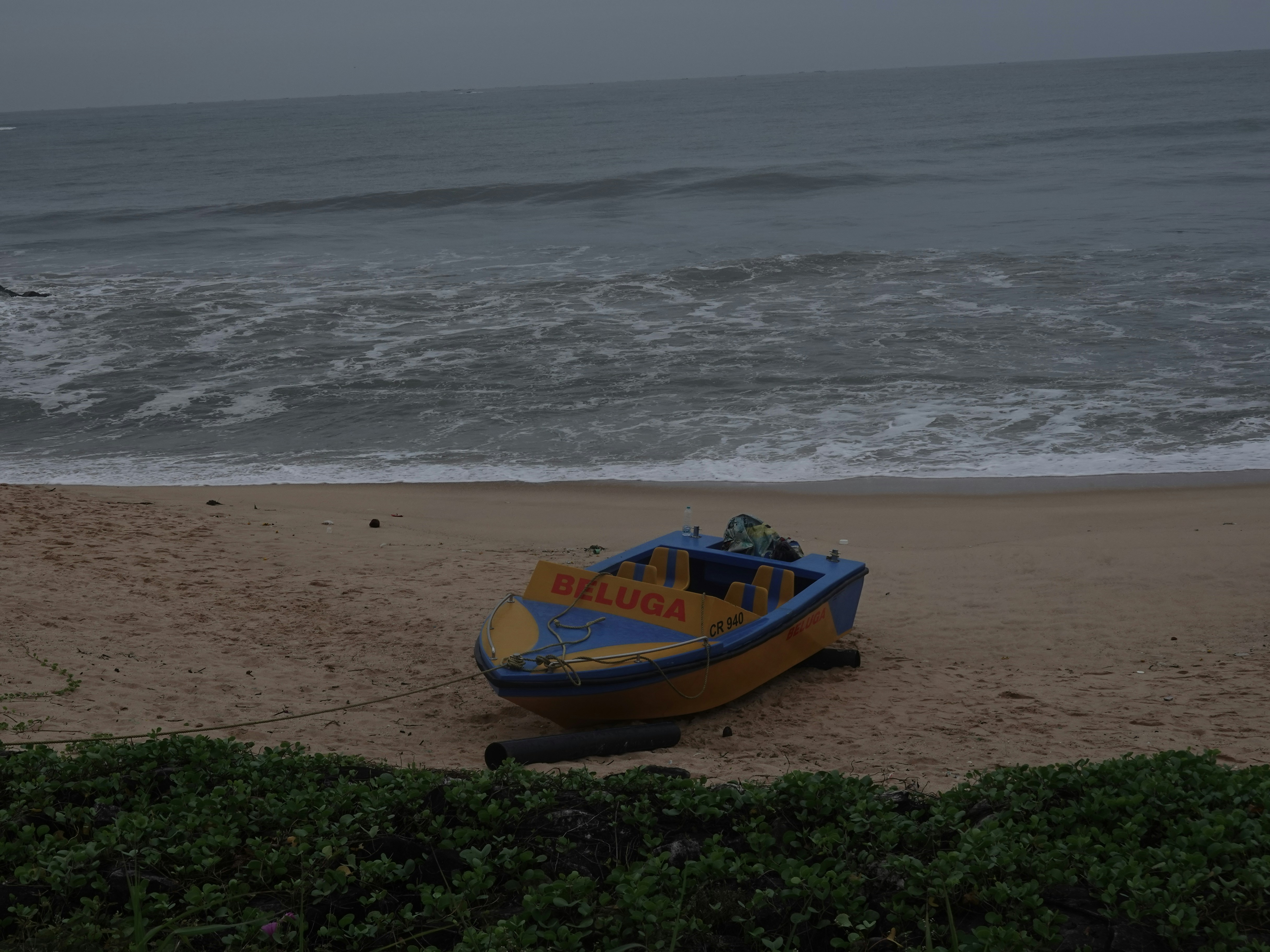 Blue Boat on A Pebbled Shore under Looming Seas