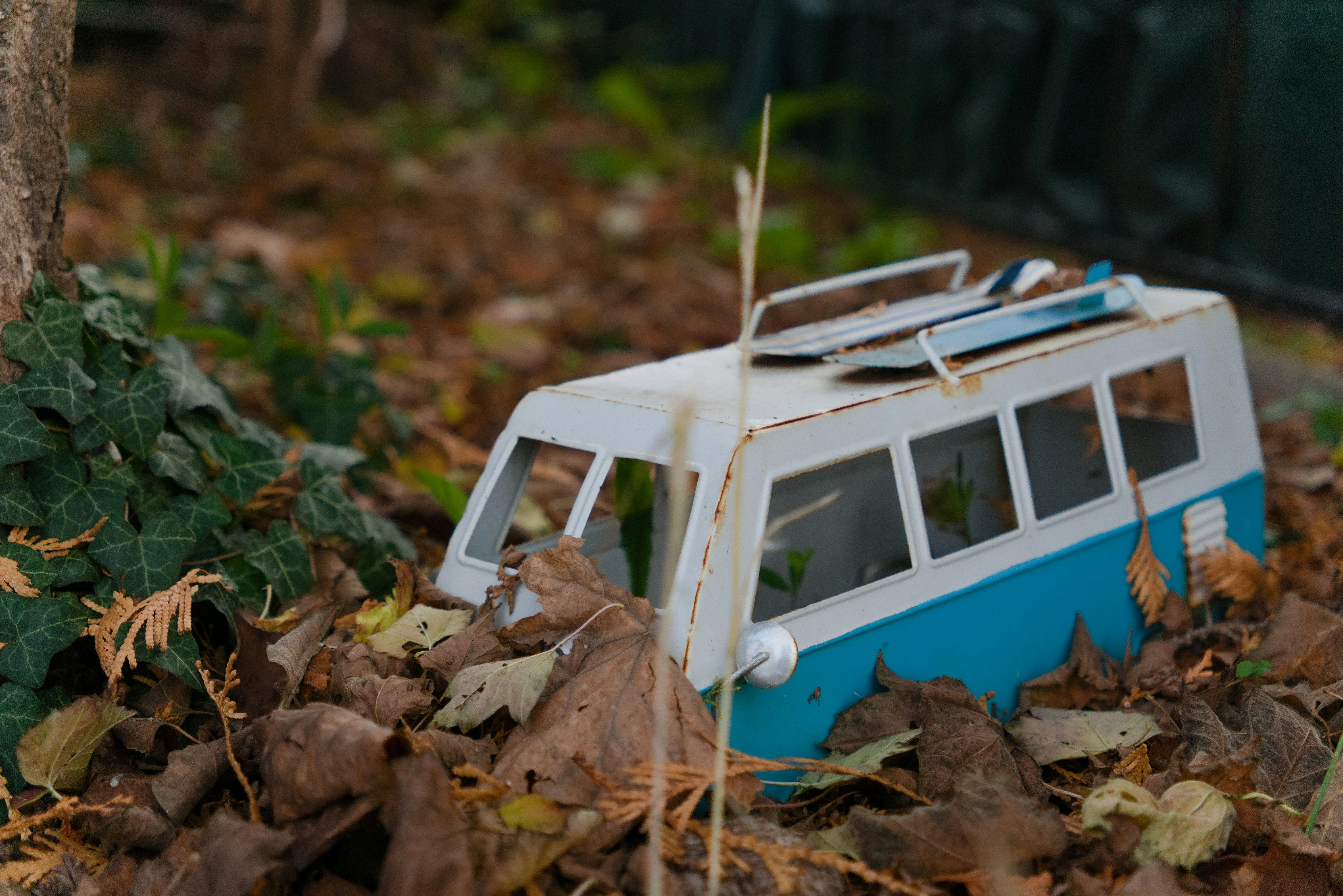 A toy bus sitting on top of a pile of leaves