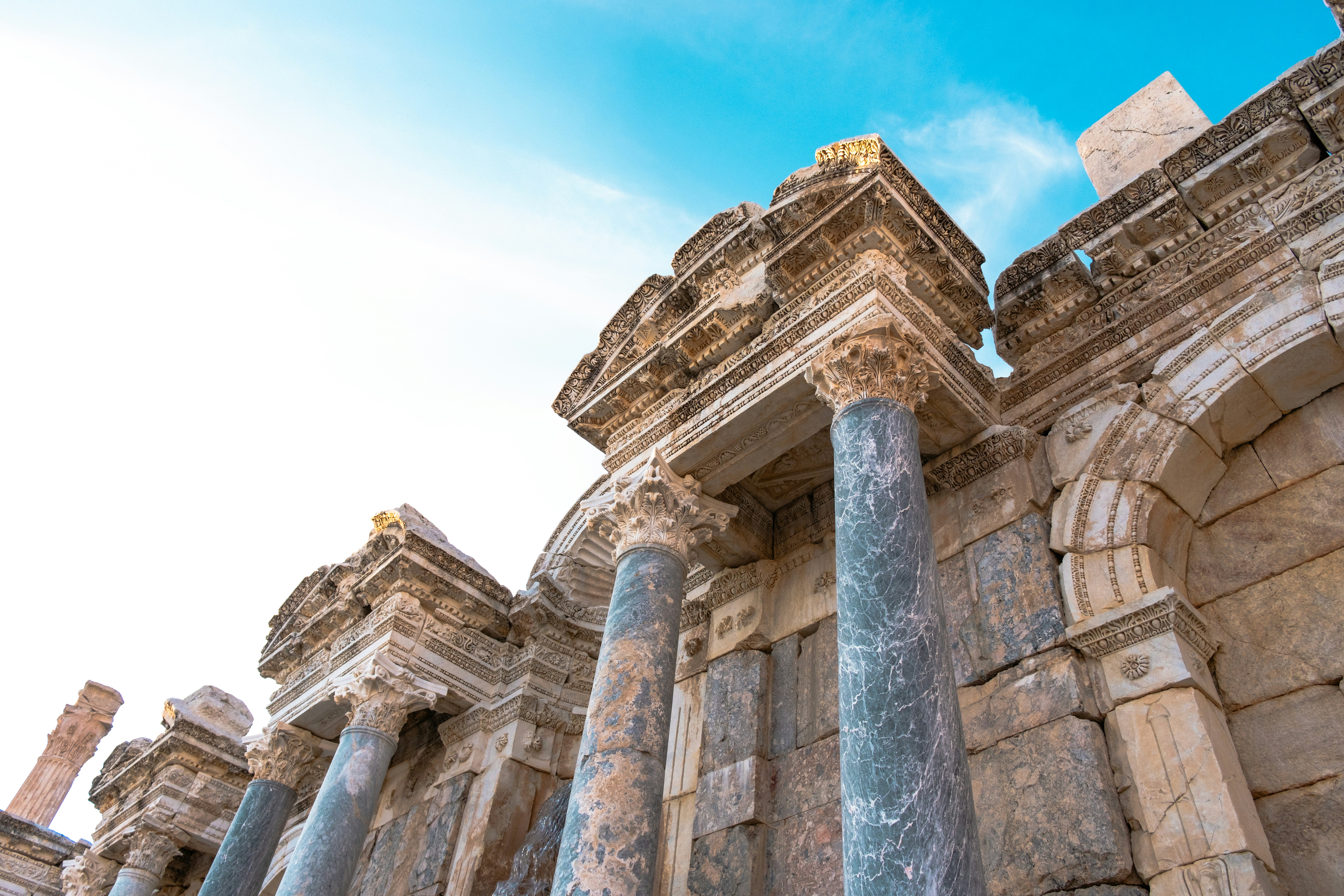 Weathered stone columns of an ancient structure under a bright blue sky.