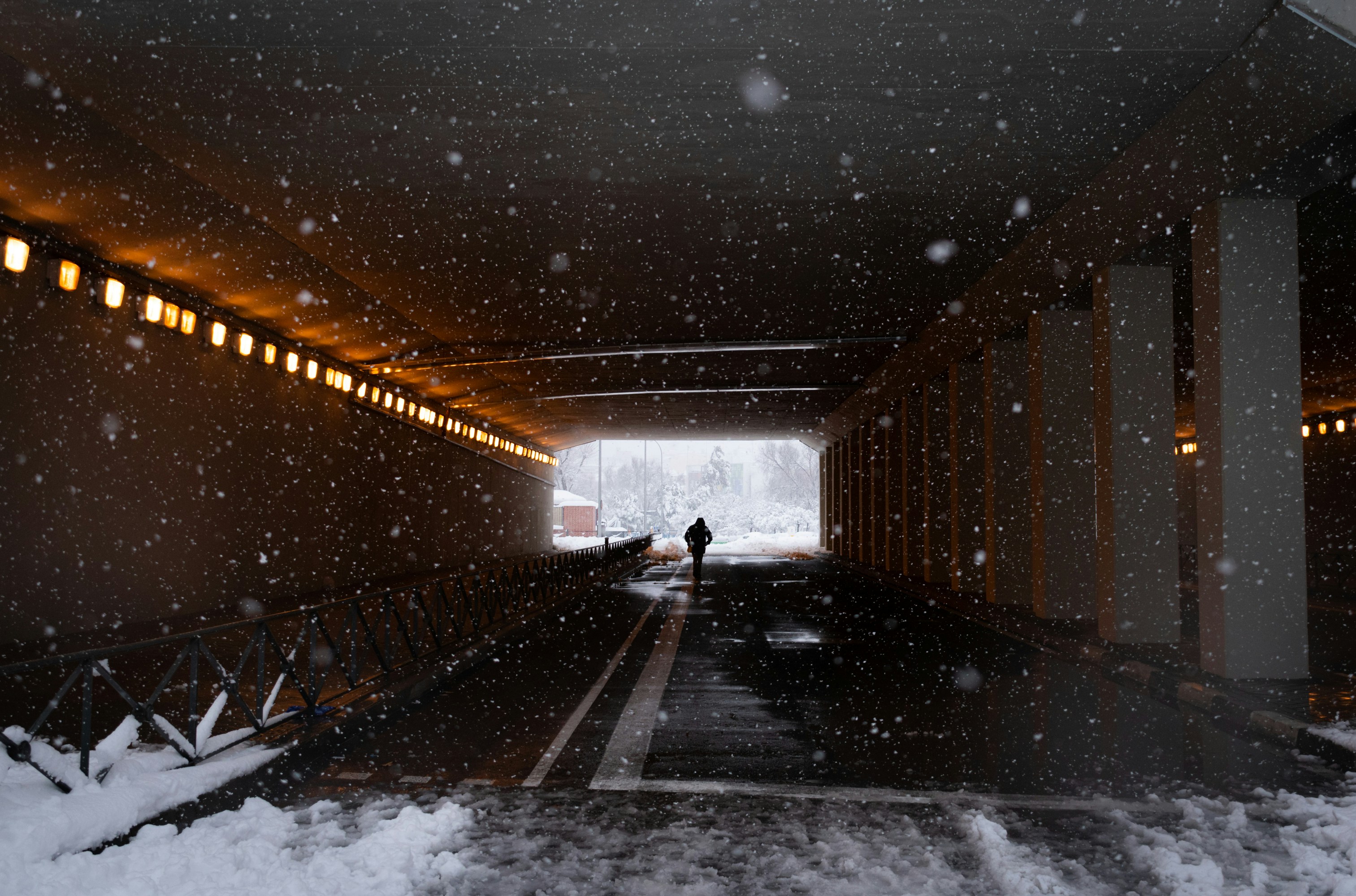 A person standing in a tunnel with snow falling on the ground photo ...
