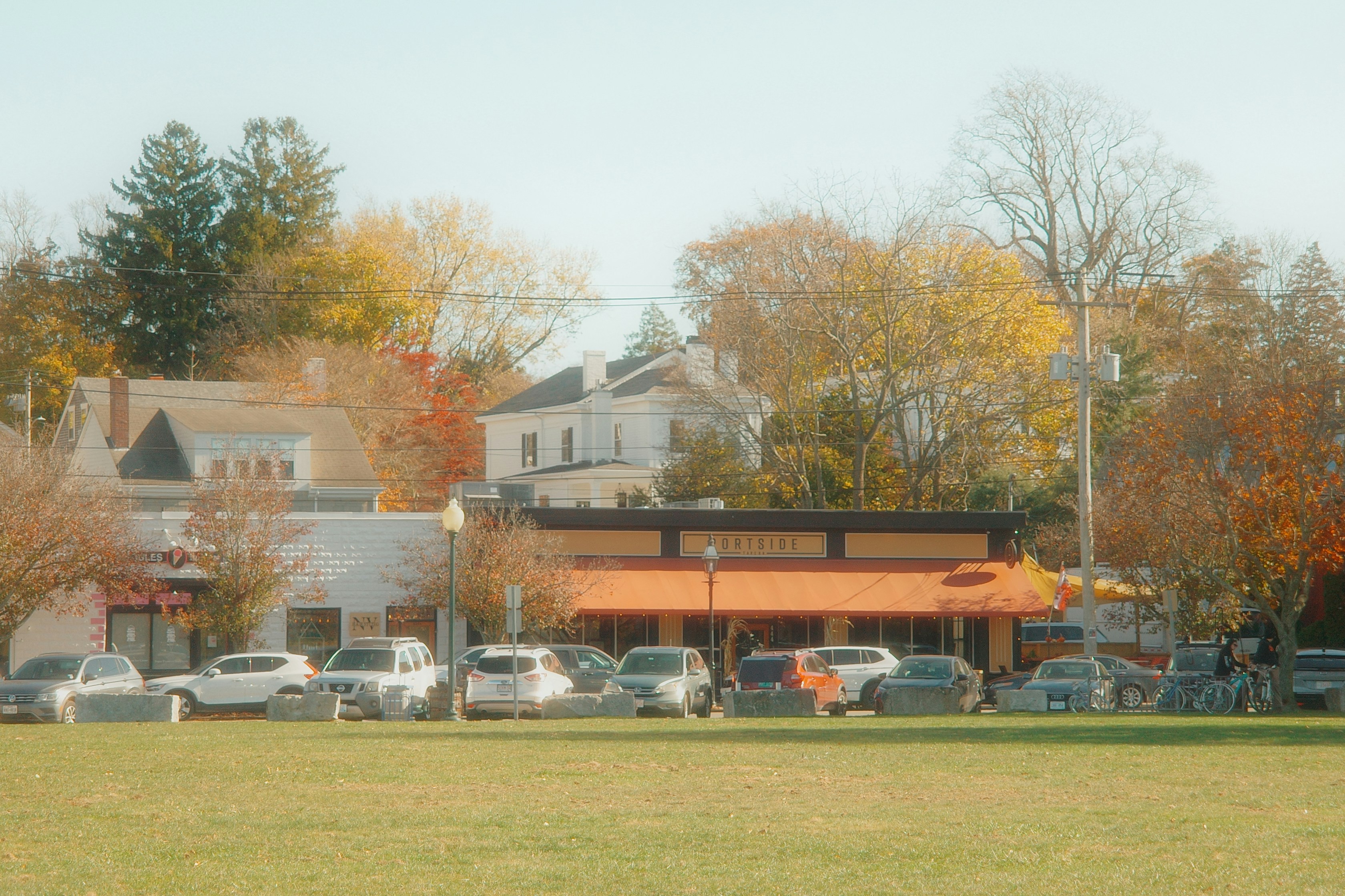 Charming storefronts adorned with fall foliage create a warm atmosphere in a small town. The scene captures the essence of community life during autumn.