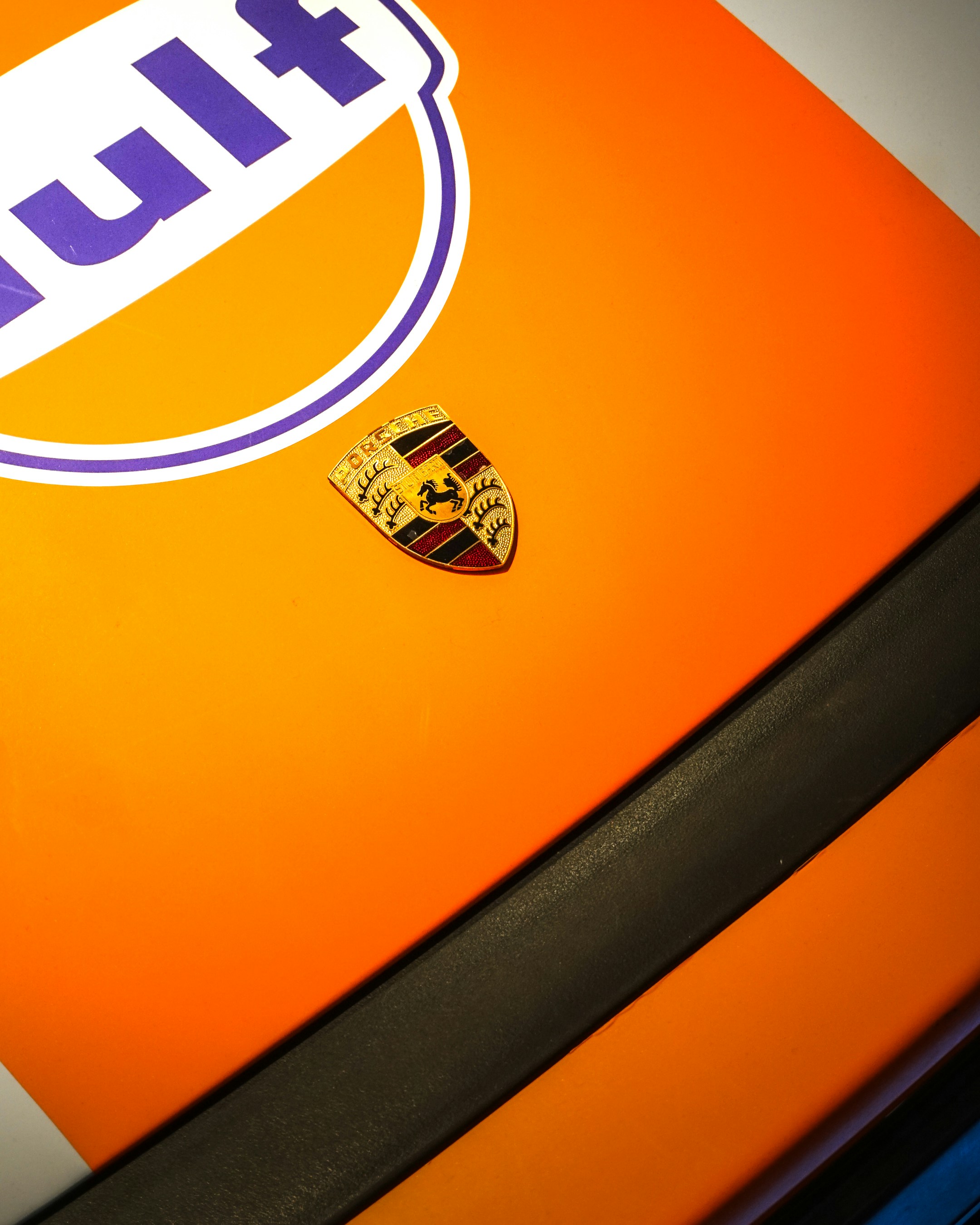 Porsche Crest on Gulf Orange Panel: Close-Range Branding in High-Contrast Color