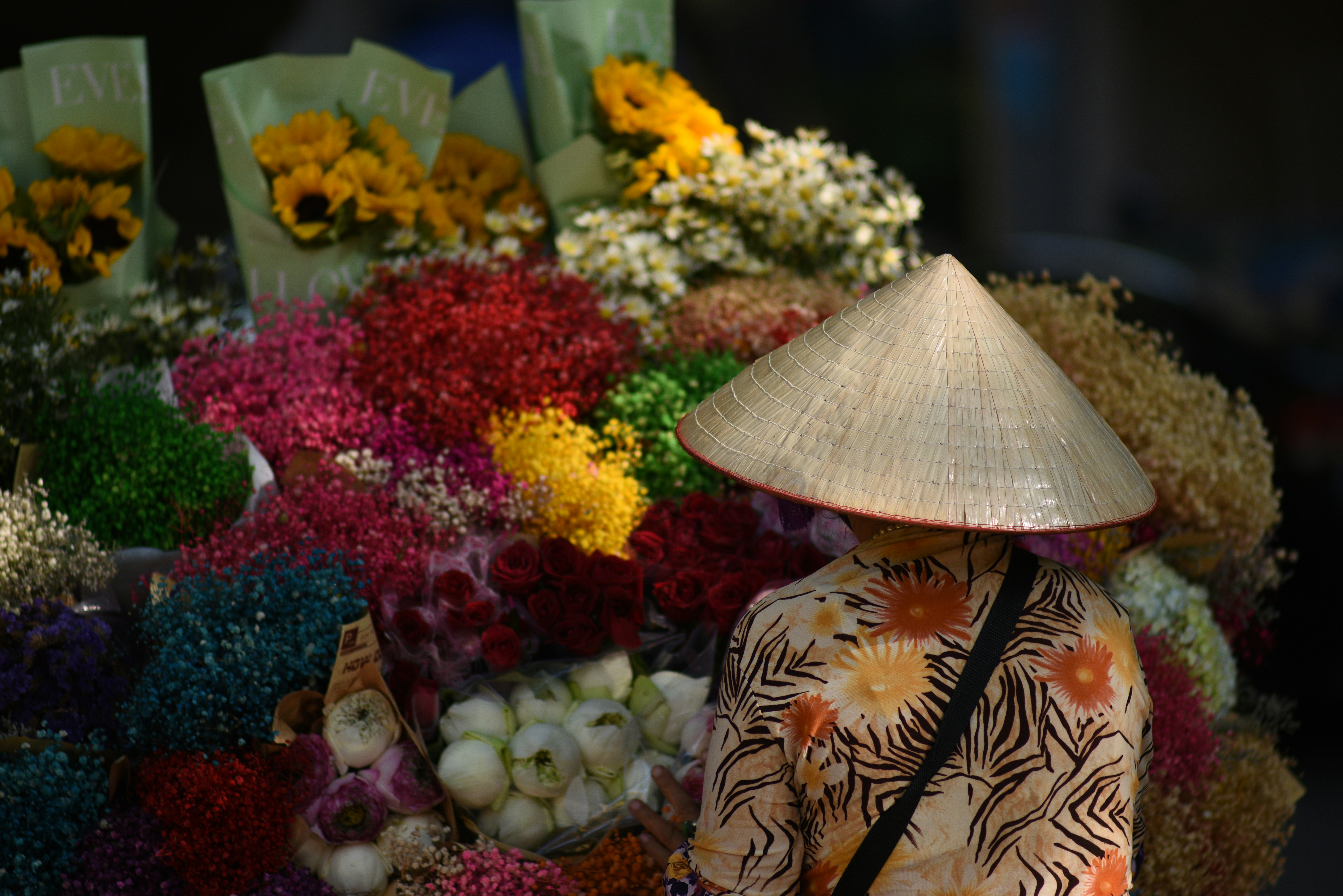 Conical Hat and a Mosaic of Blooms: A Street Flower Stall Portrait