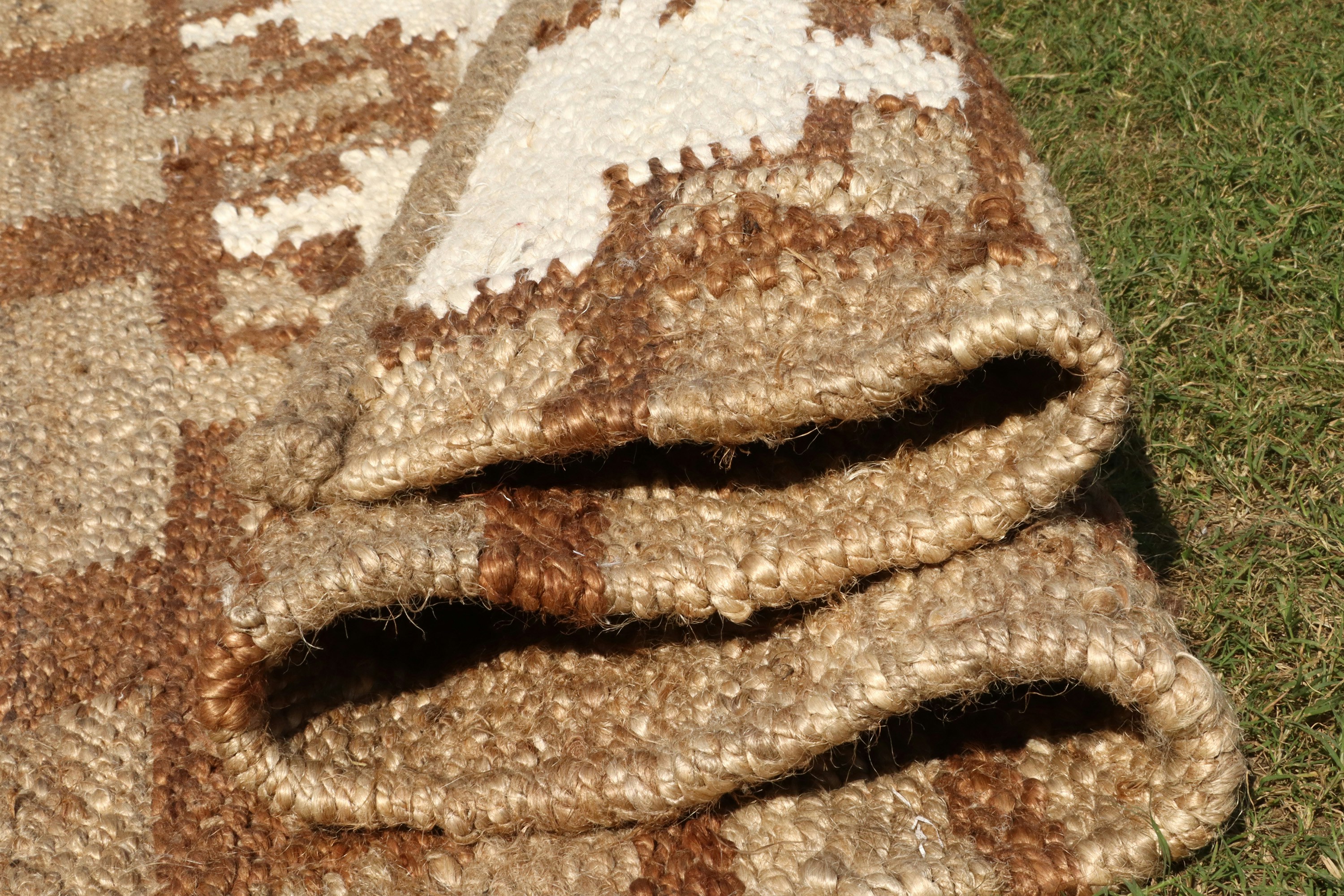 Sunlit Fold: a woven rug's curves resting on a grassy canvas