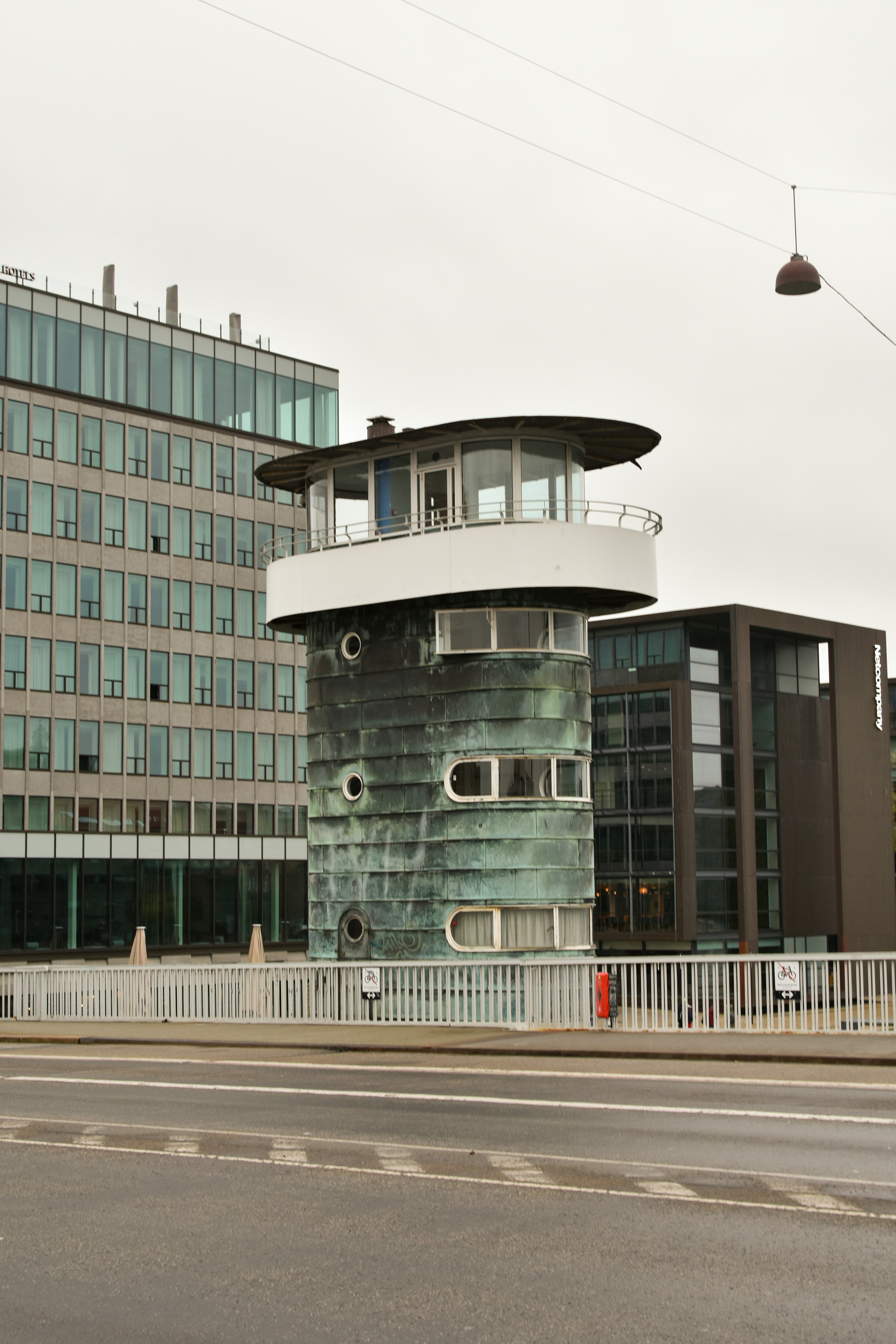 Patina Cylinder Towers Over a Glass-Block Cityscape