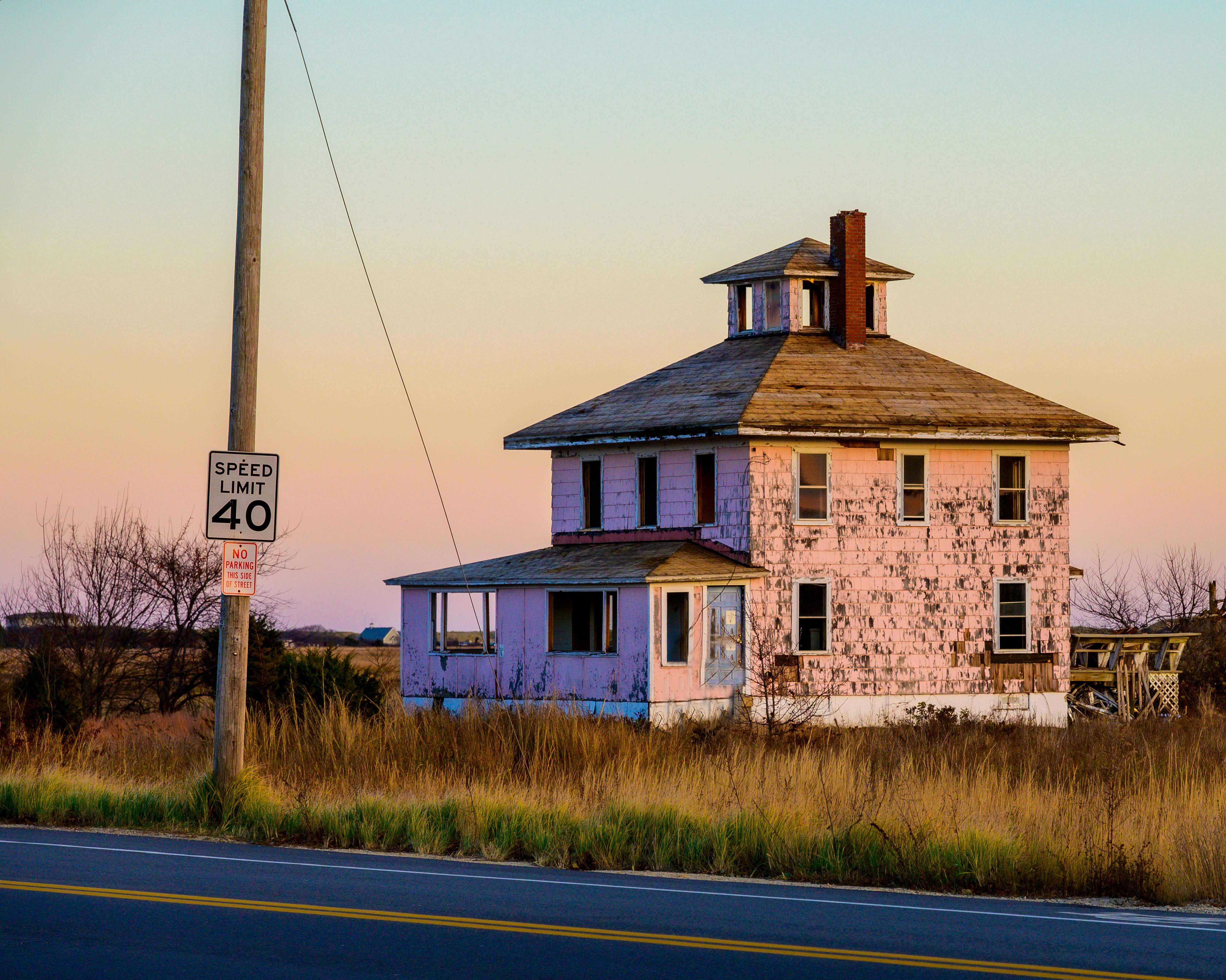 A run down house sitting on the side of a road photo – Free The pink ...
