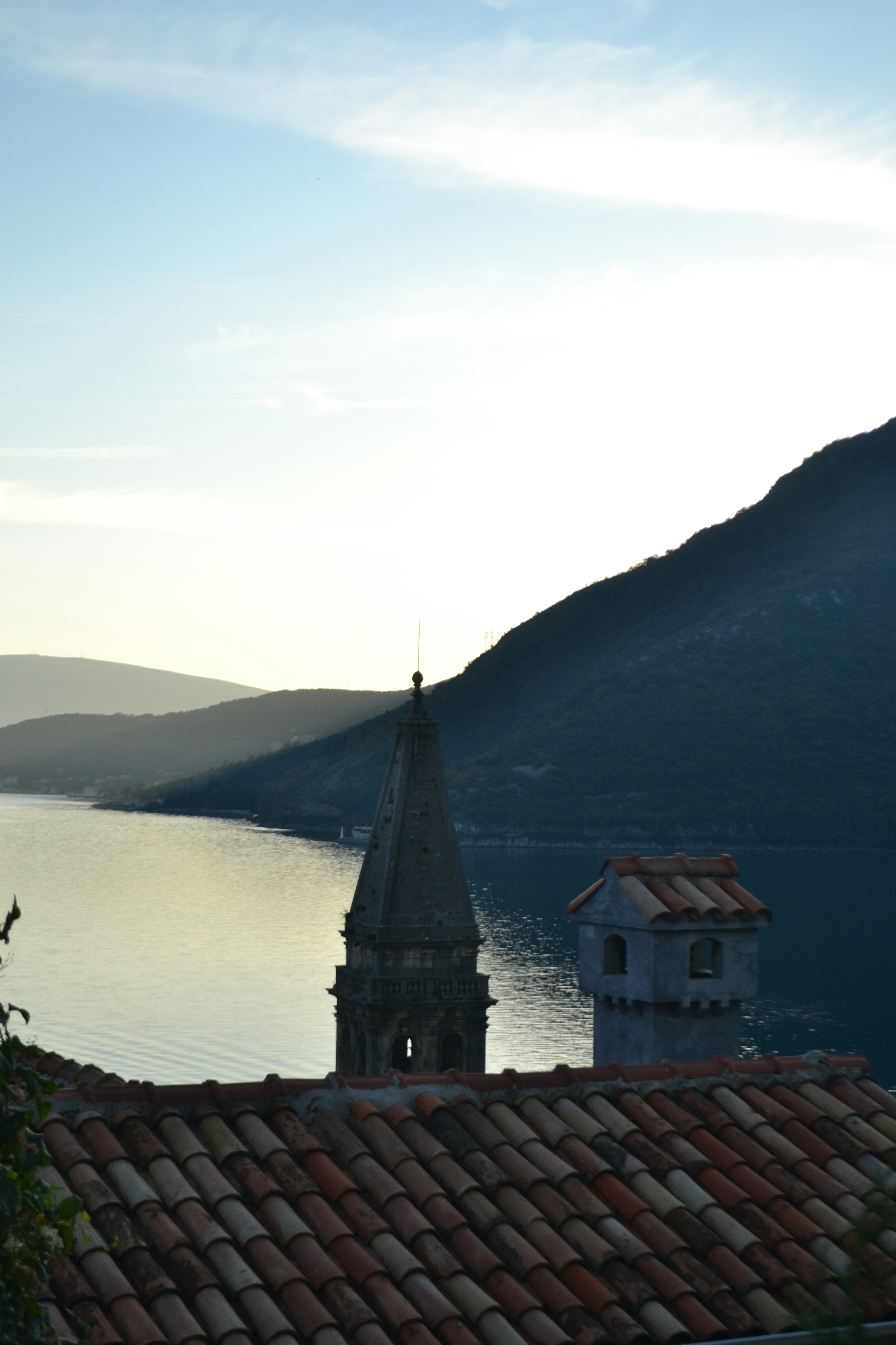 Rooftop Silhouette: Spire Against Quiet Lake and Mountain