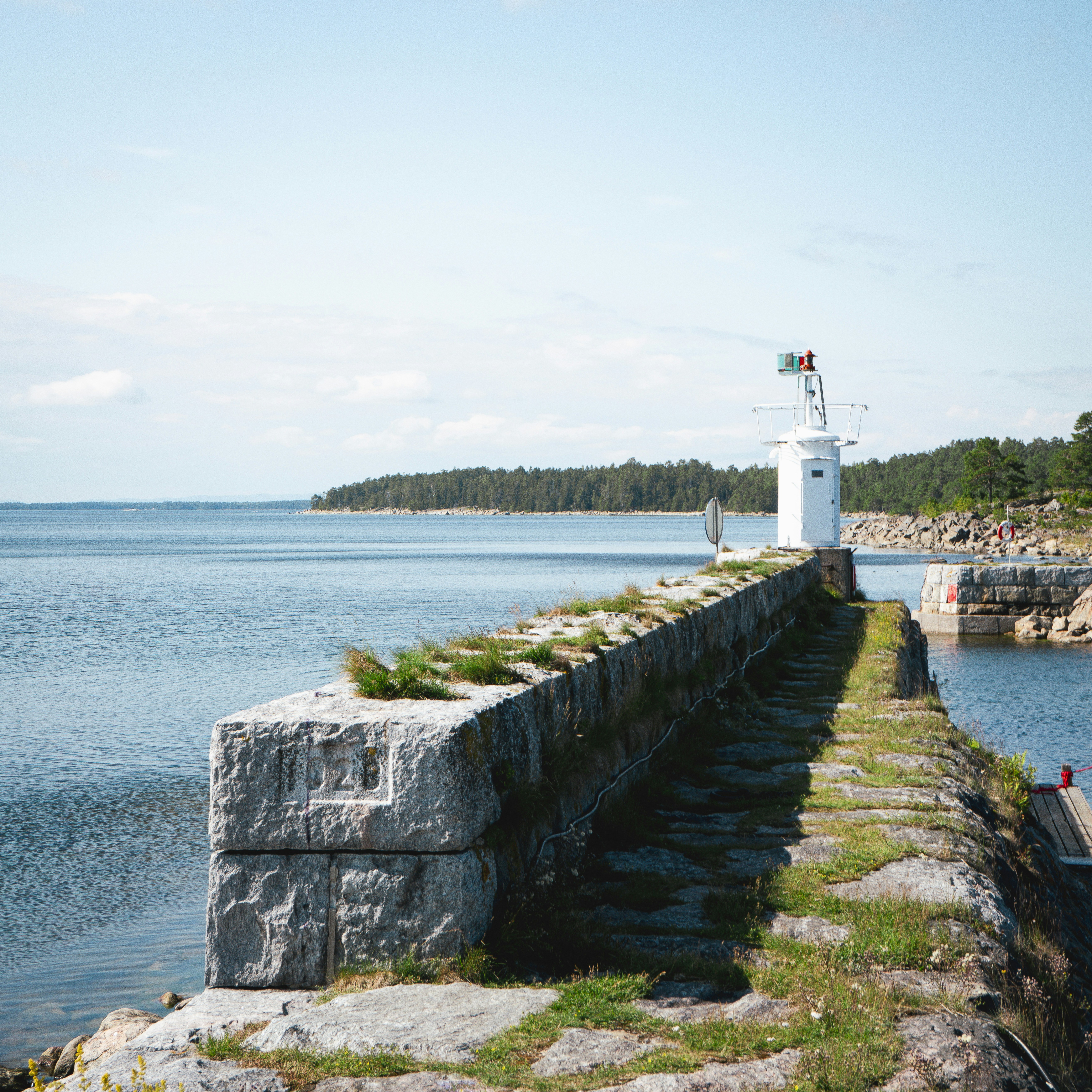 A lighthouse on the edge of a body of water photo – Free Höllviken ...