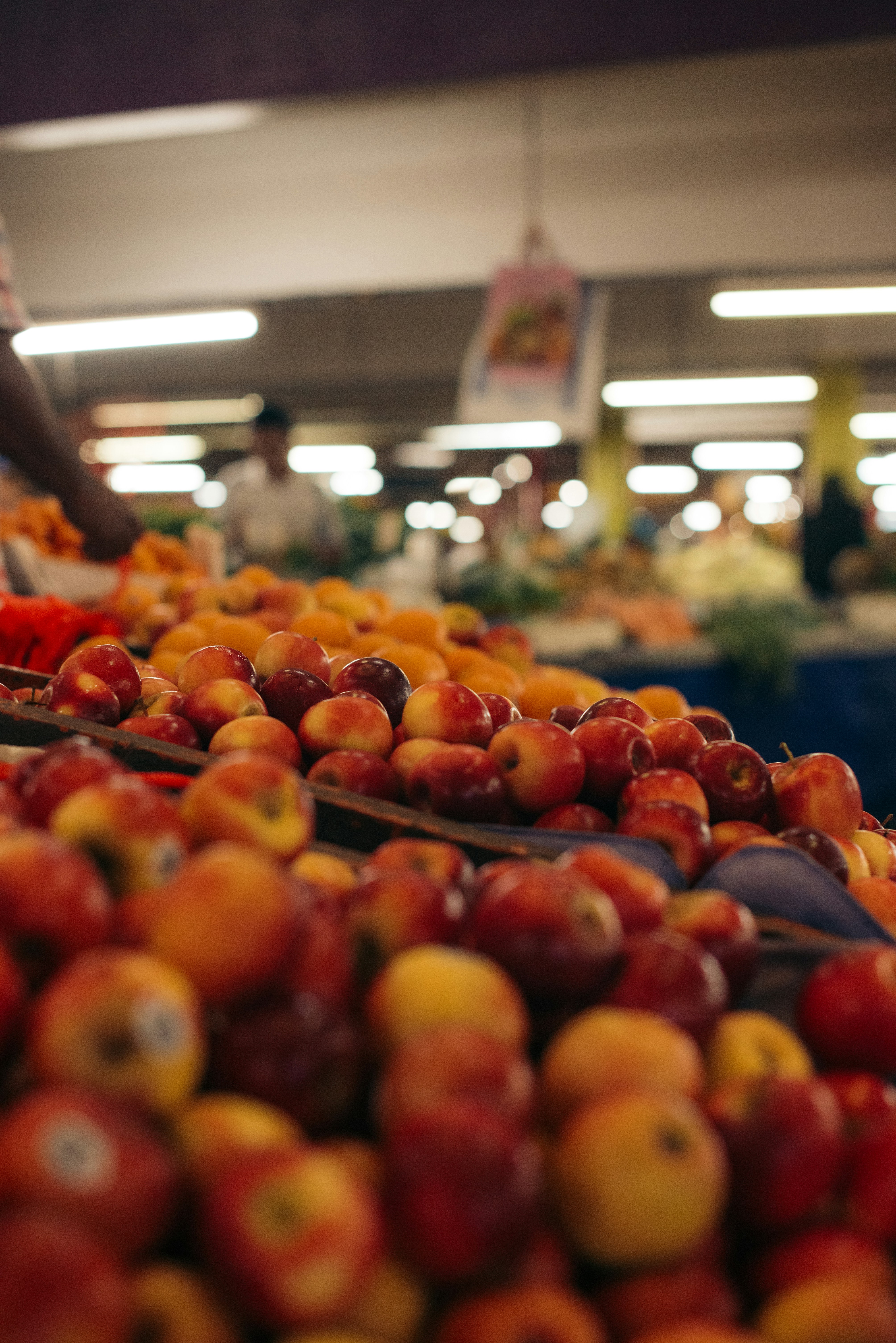 Red Harvest at Market Edge: Apples in a Soft, Bustling Glow