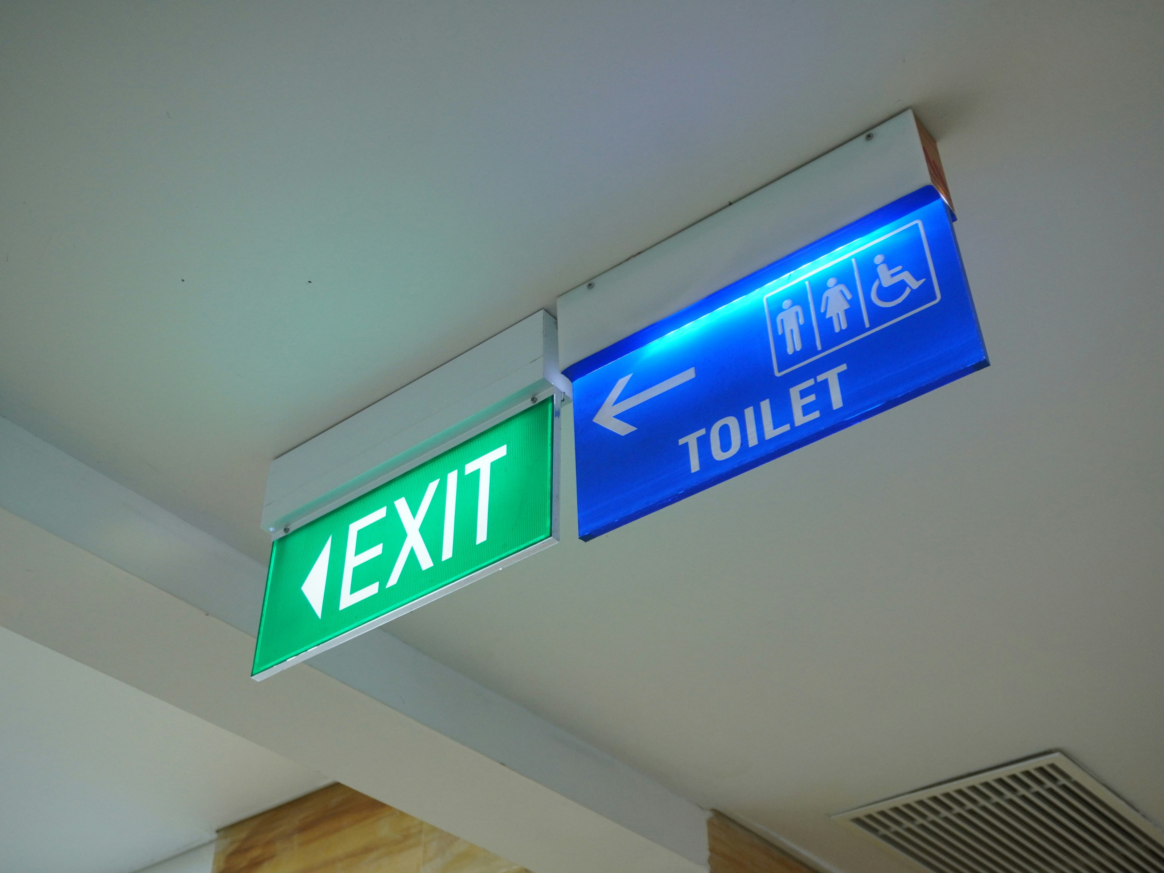 A blue and green exit sign hanging from a ceiling photo – Free Sign ...