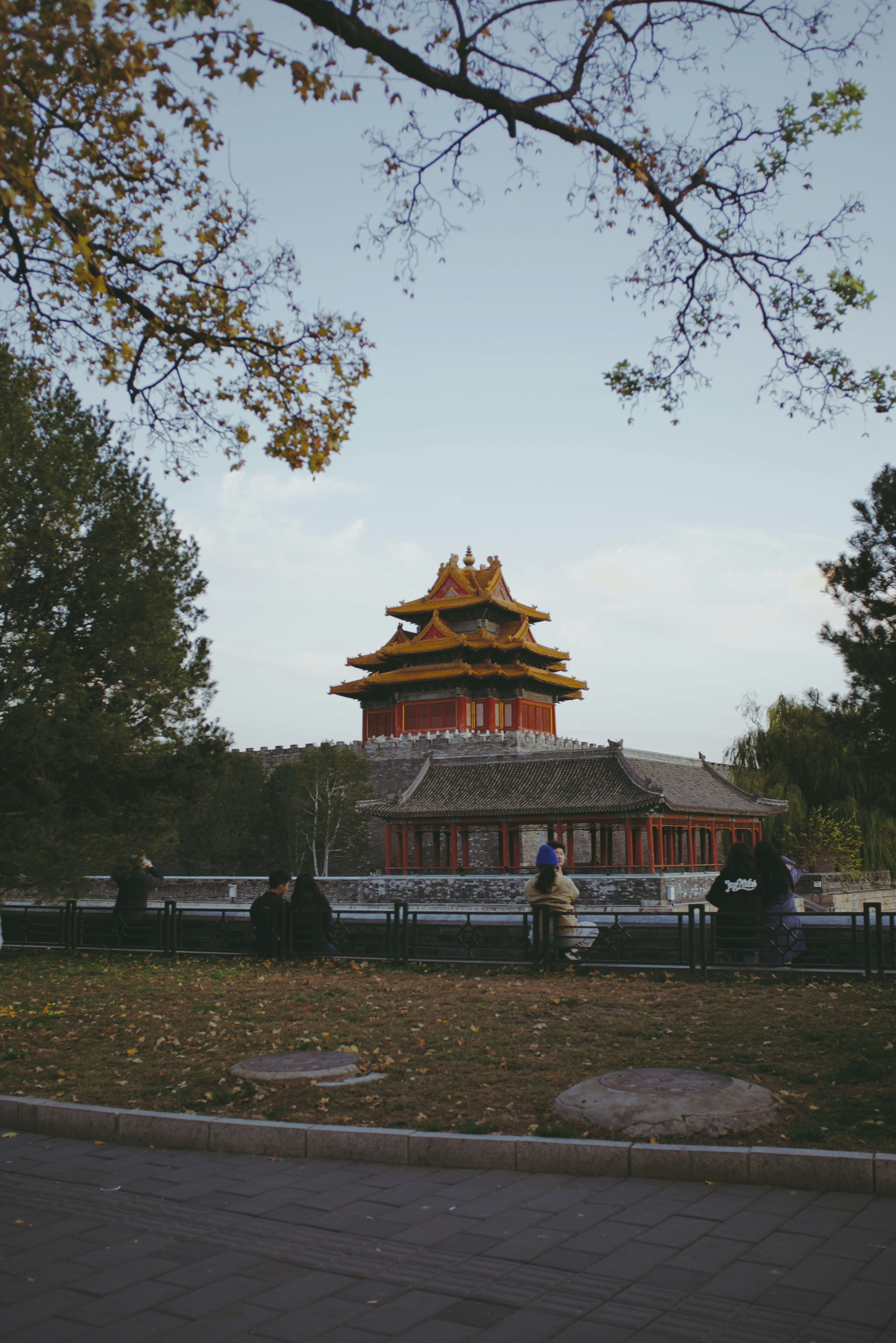 Traditional Chinese pavilion surrounded by trees and visitors, reflecting cultural heritage in a tranquil park setting.
