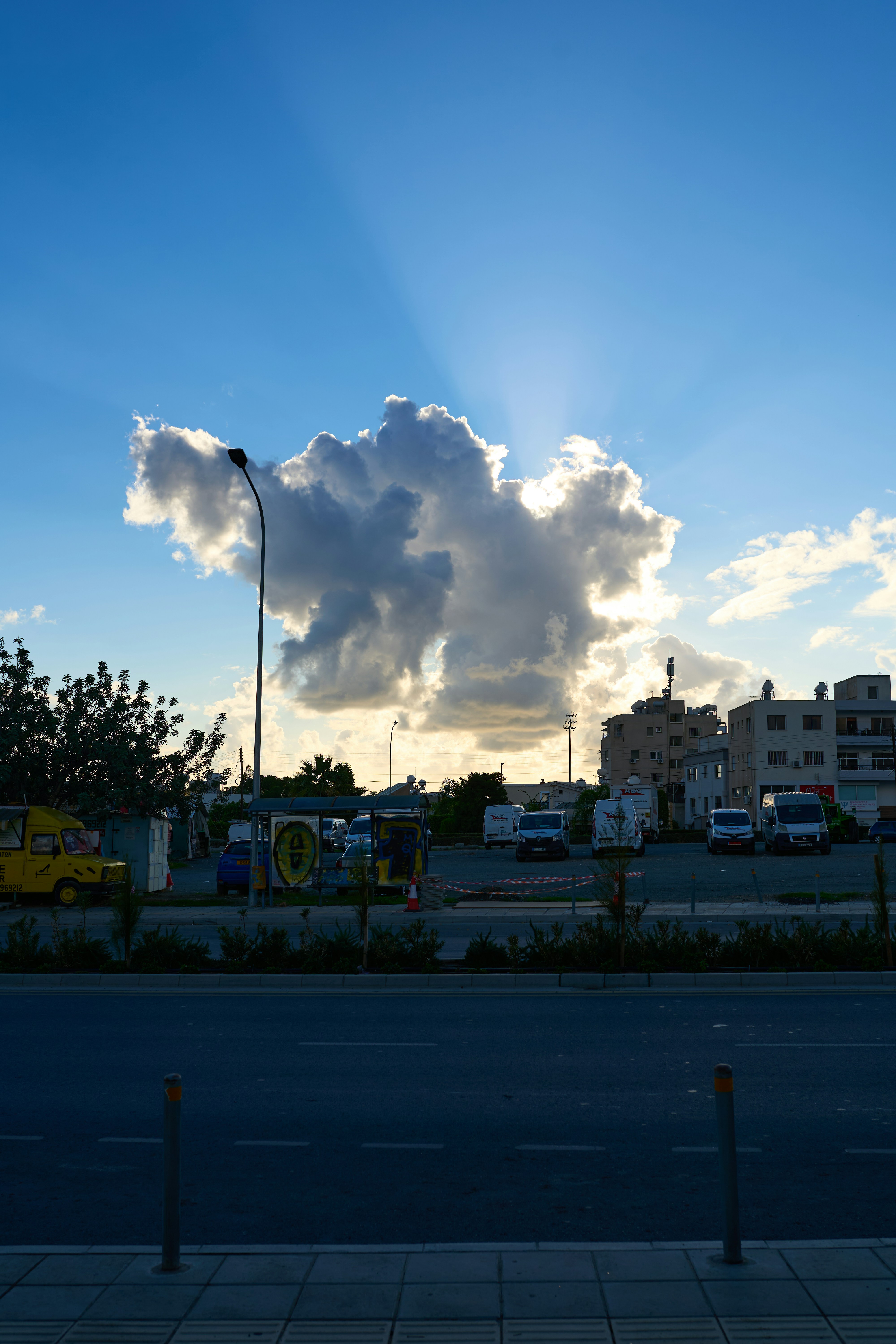 Sunburst over the urban boulevard: cloud sculpture above a quiet street