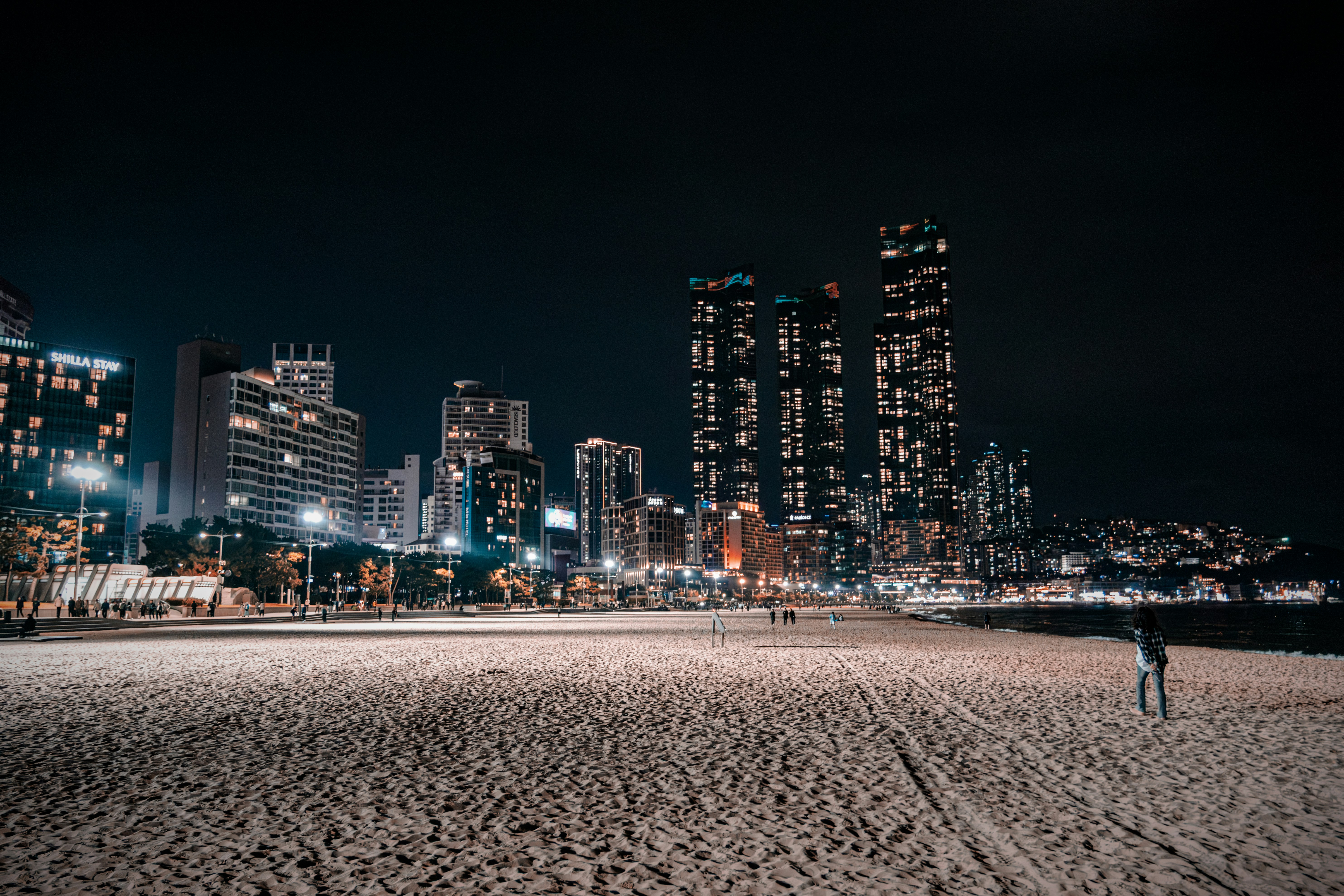 Neon Skyline Over Quiet Sand: Nightscape by the Lone Figure