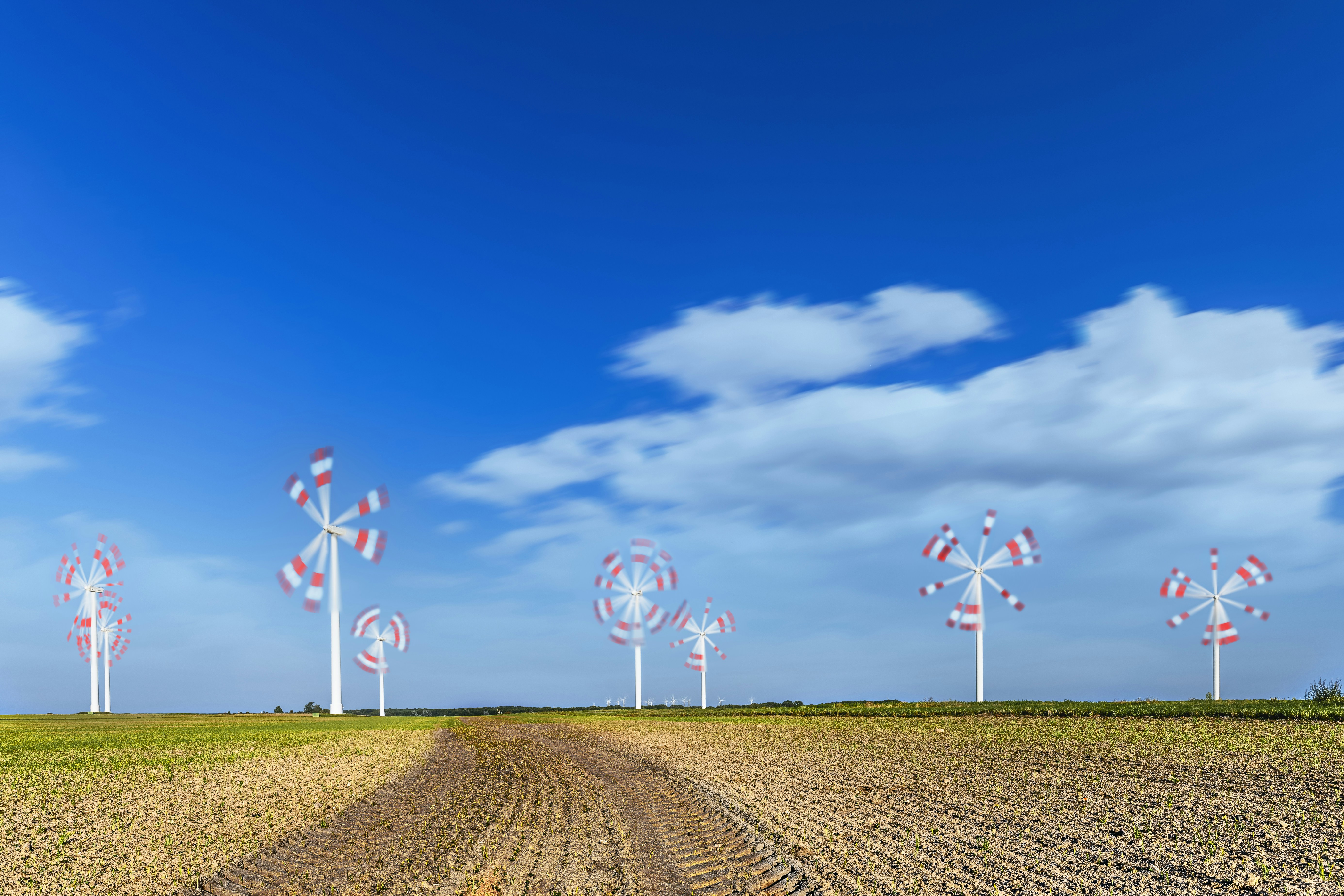 Pinwheel Sentinels: Striped Windmills Across a Flat Prairie