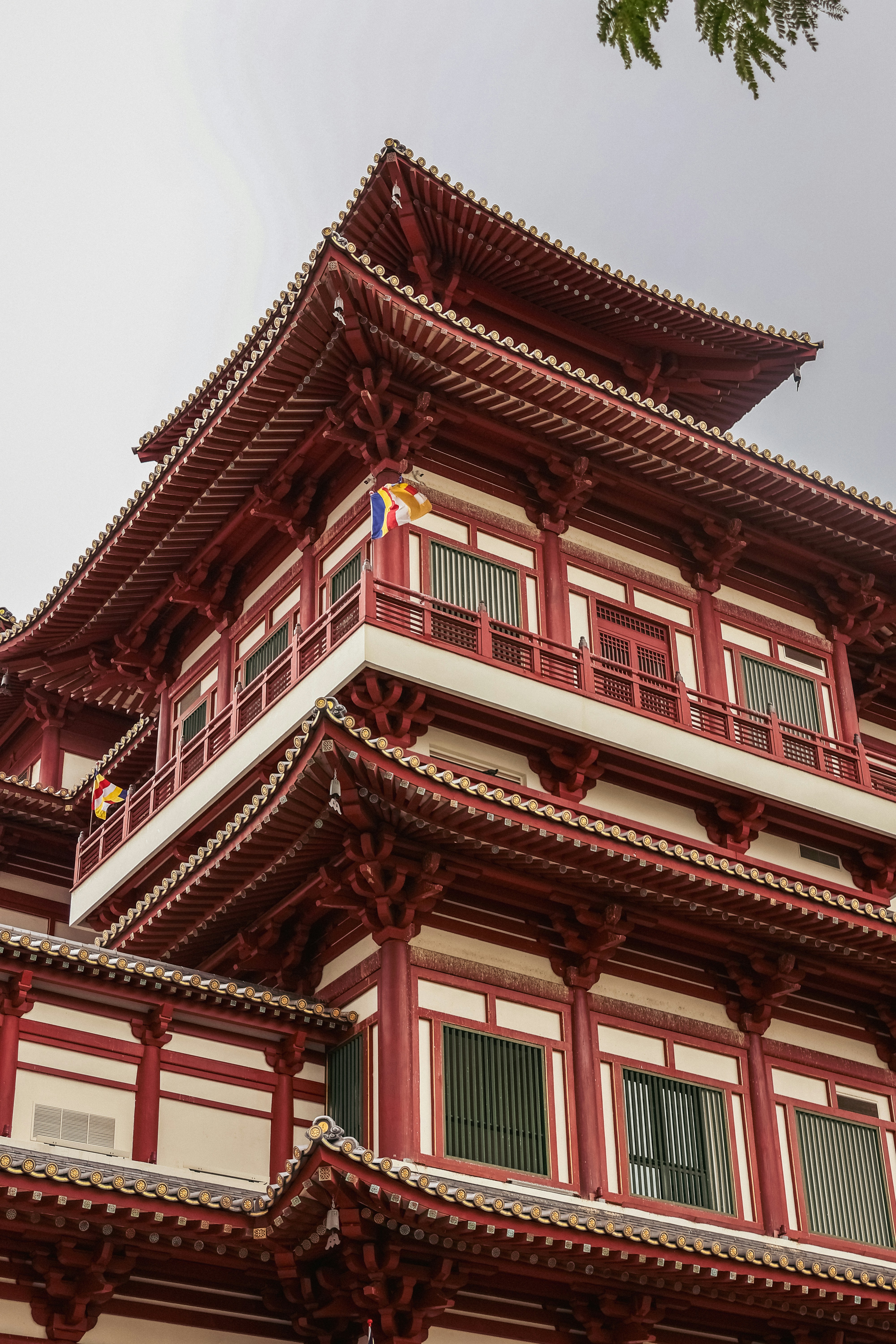 A mesmerizing buddhist temple in the heart of Singapore | A tall red and white building sitting under a cloudy sky