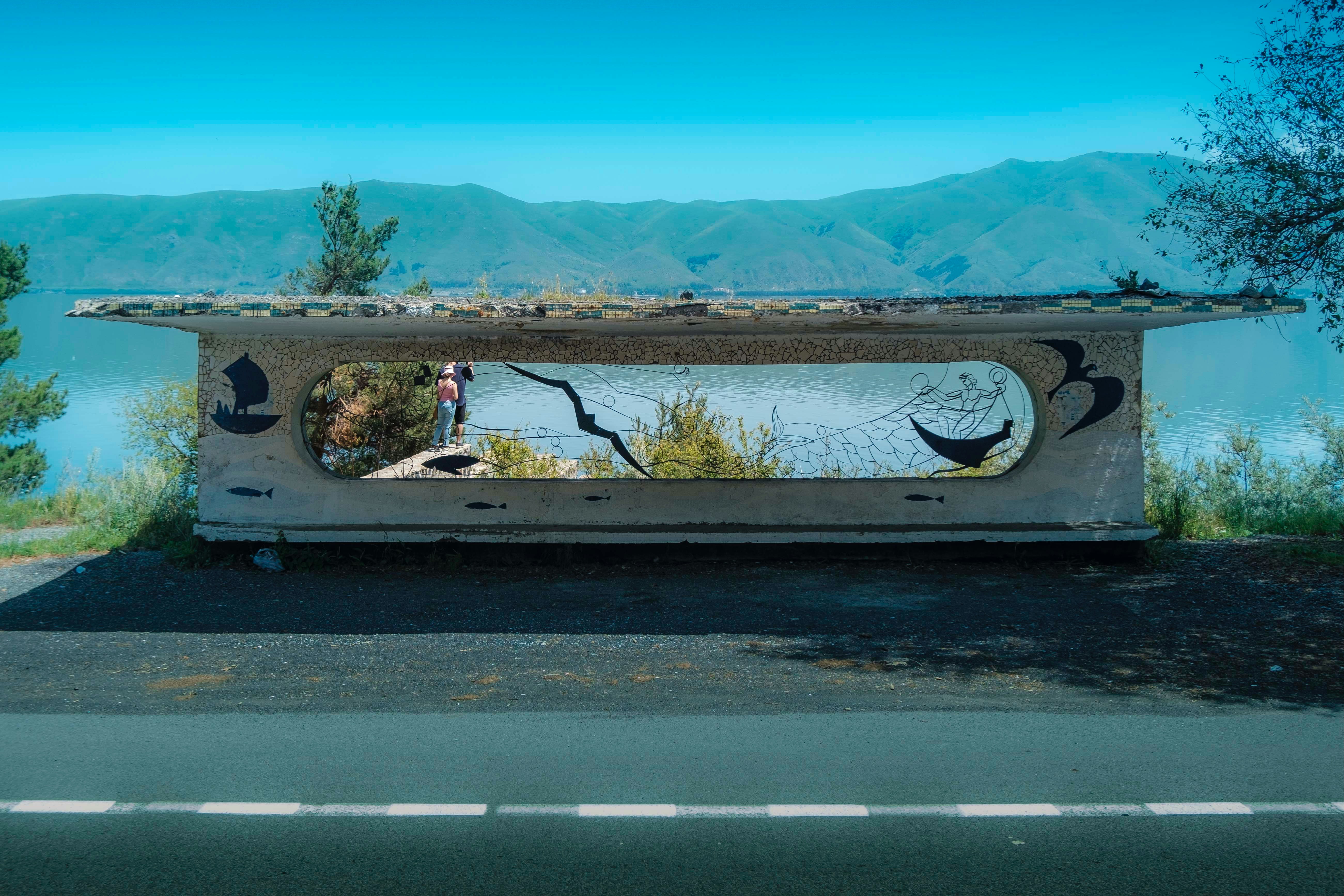 Windowed Shelter Framing a Lakeside Vista with a Lone Figure