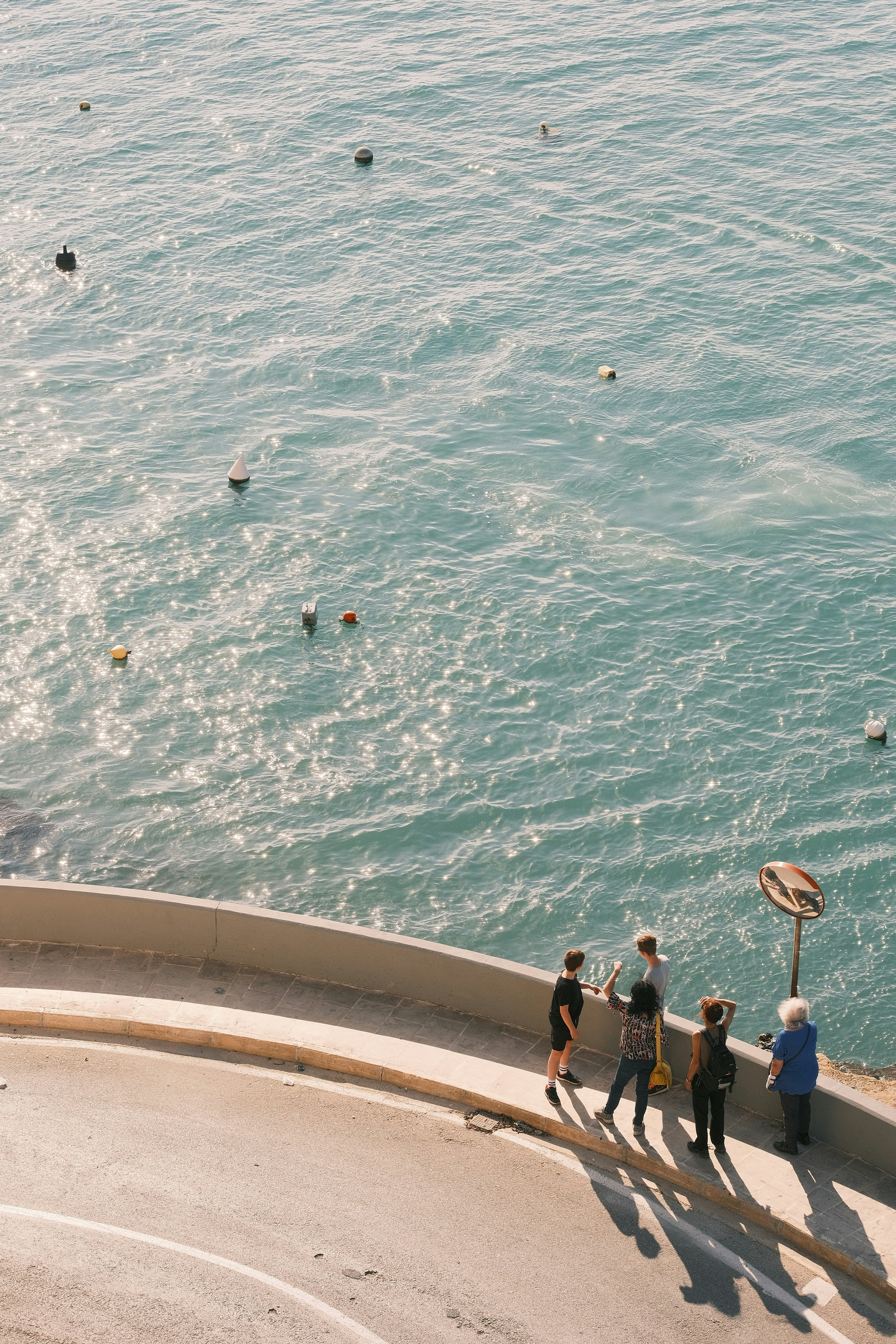 Sunlit Seawall Pause: Friends Along a Turquoise Tide