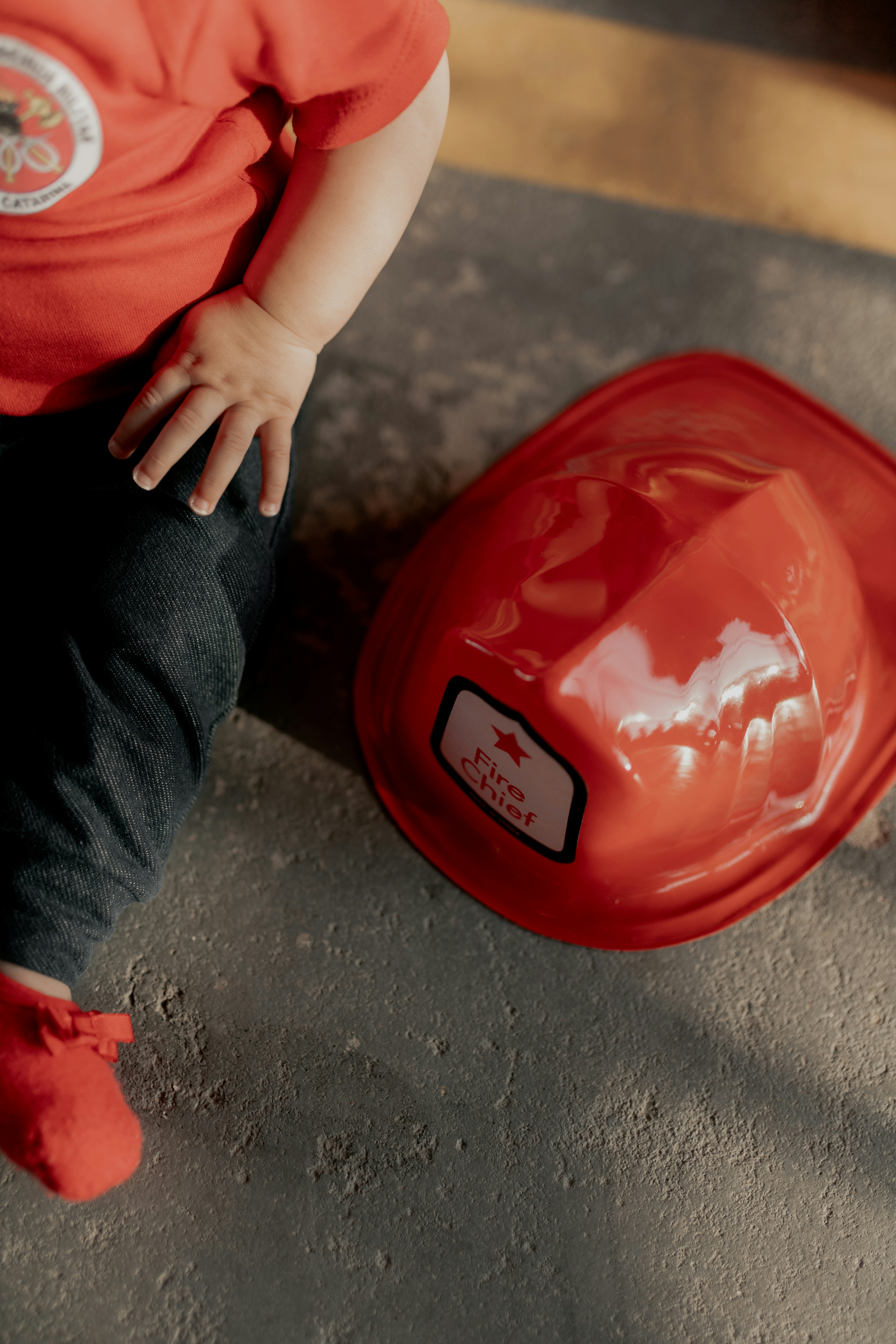 Tiny Hand, Bold Red Helmet: A Quiet Moment on a Playground Floor