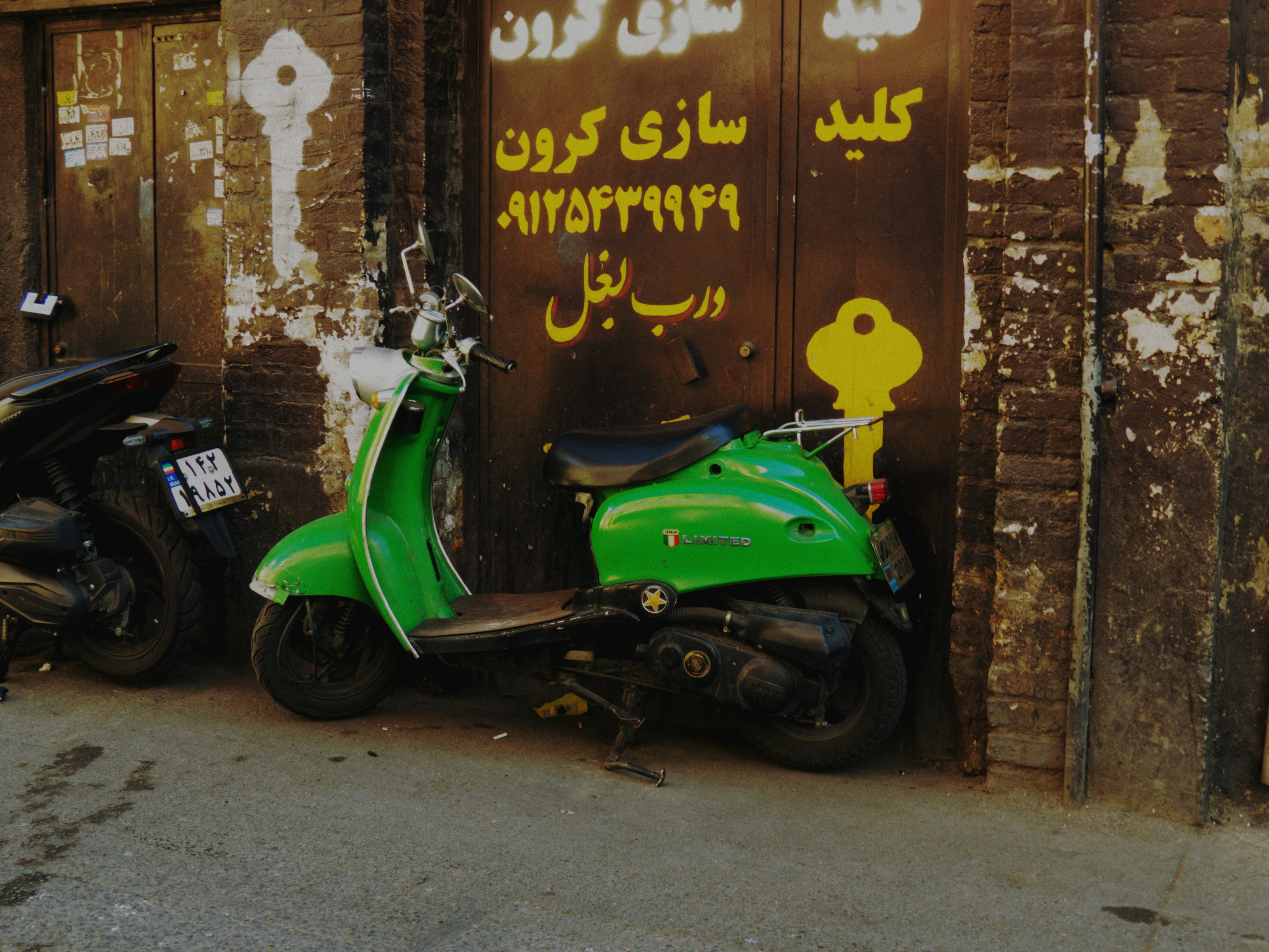 Verdant Rider: lime-green scooter tucked beside a weathered wall with Persian signage
