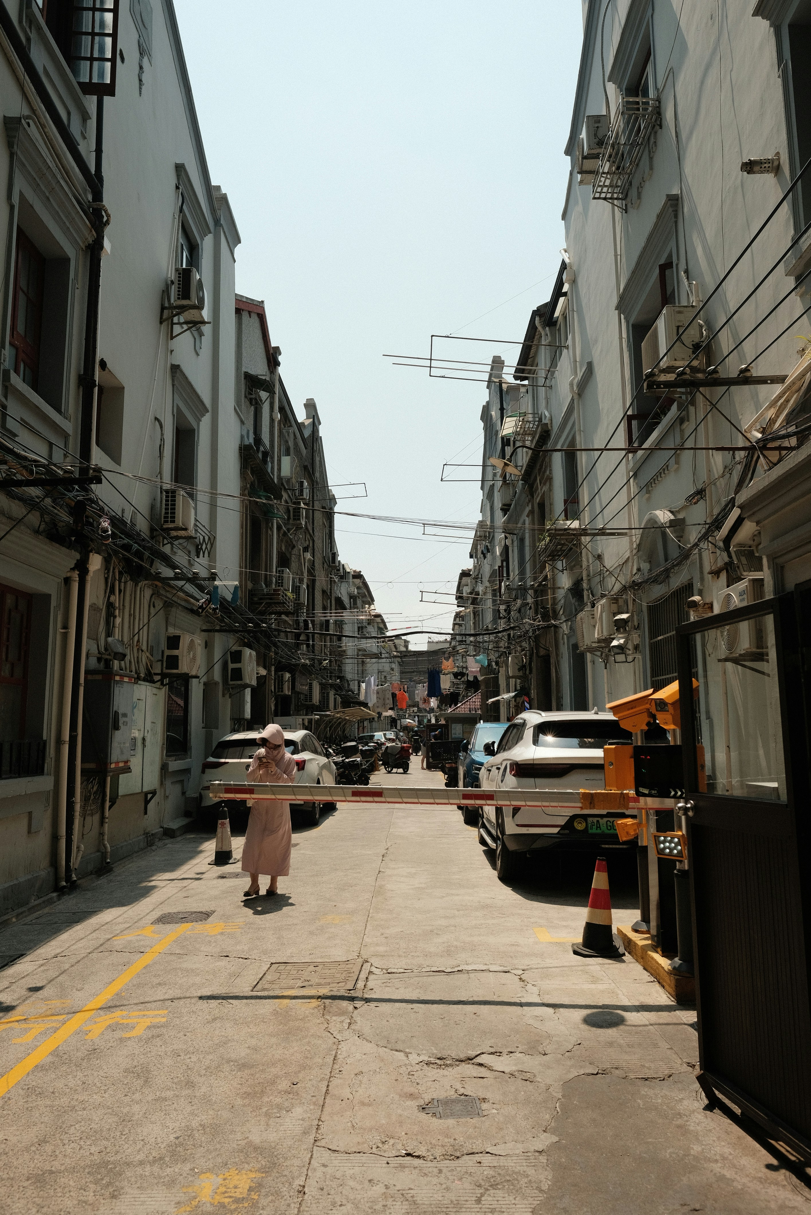 Pink Dress in a Narrow Urban Alley: Quiet Moment Under a Web of Wires