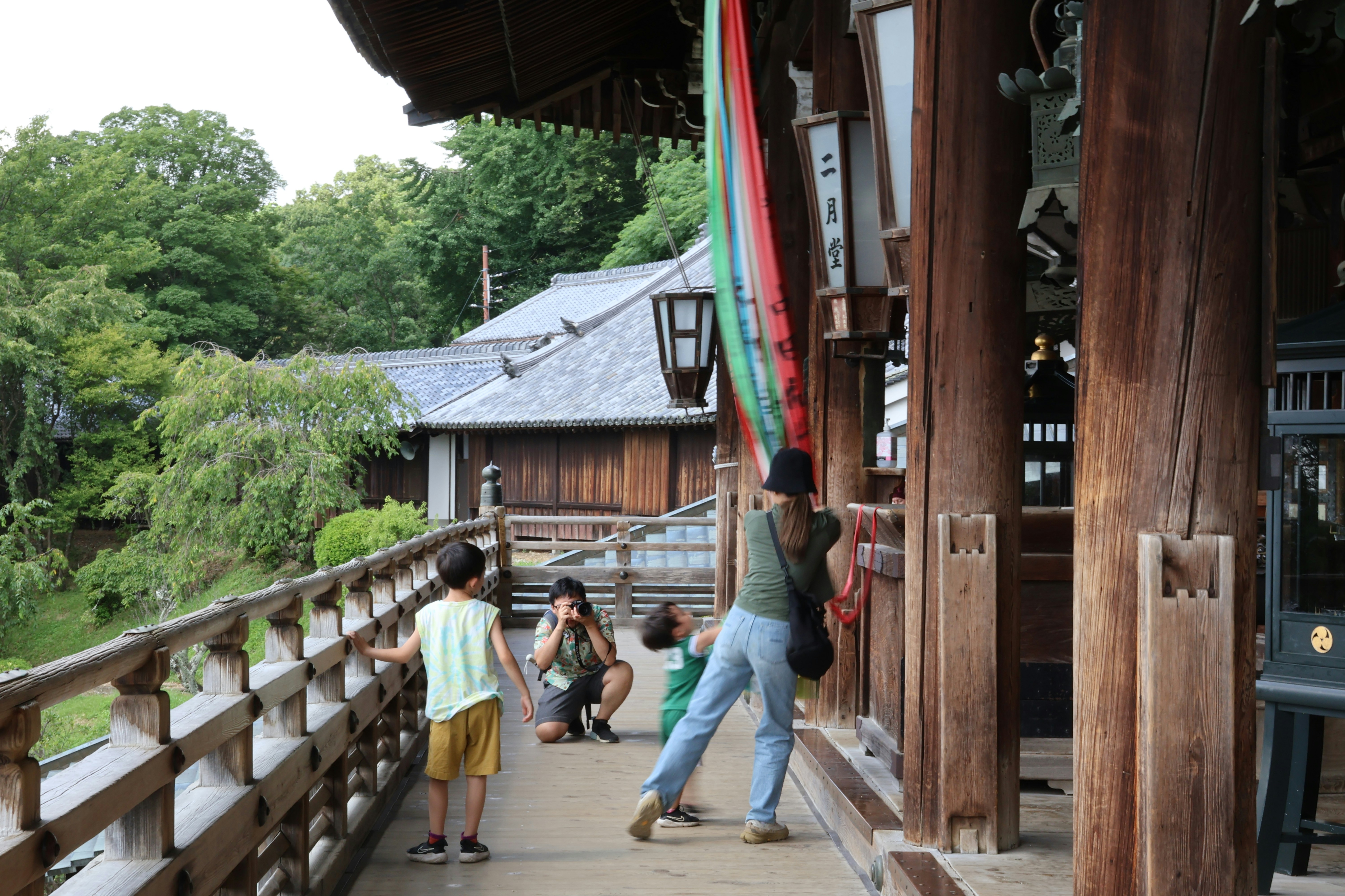 Timber Veranda Moment: A Crouching Photographer Among Shrine Visitors
