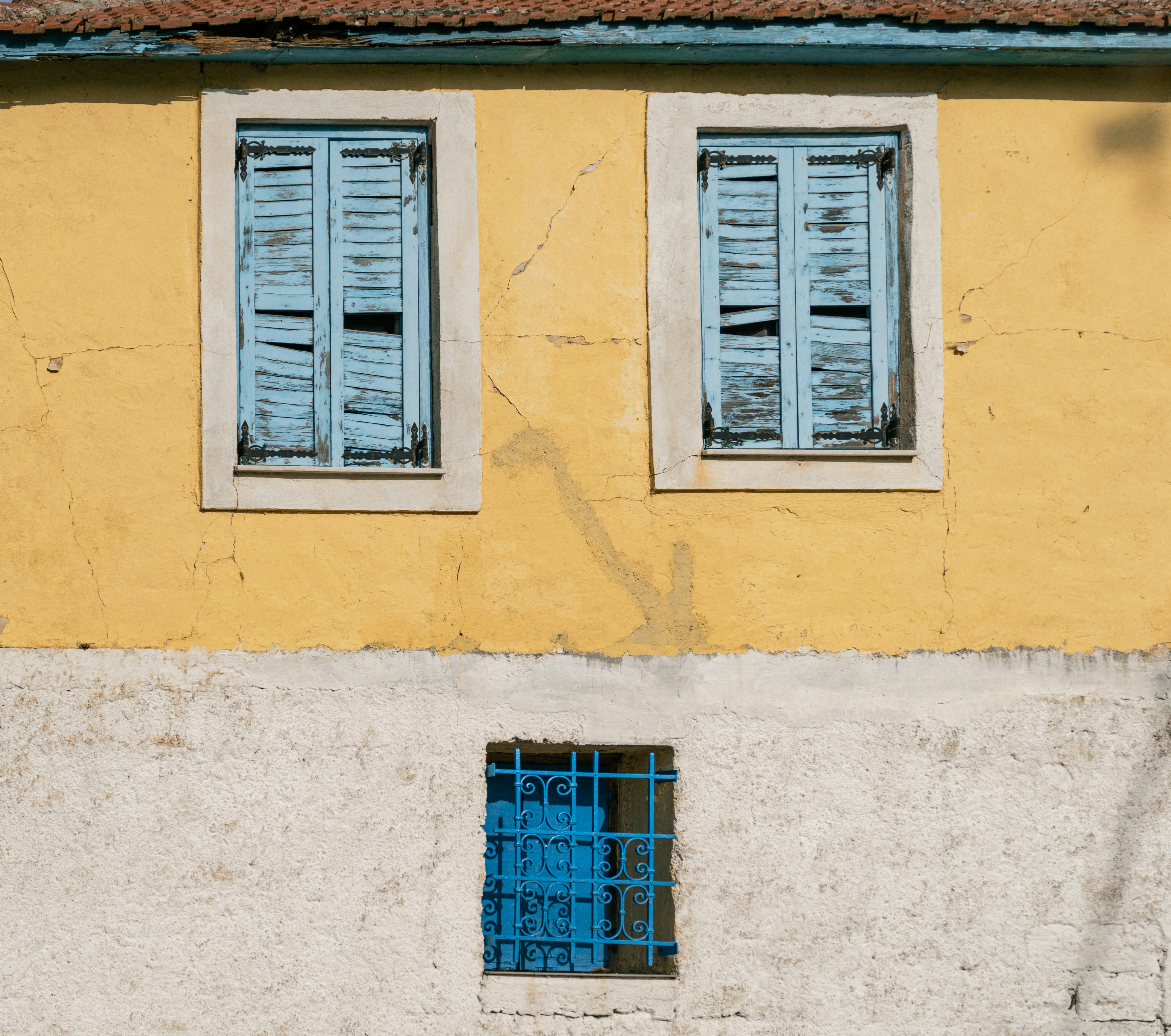 A yellow building with two windows and a blue window photo – Free ...