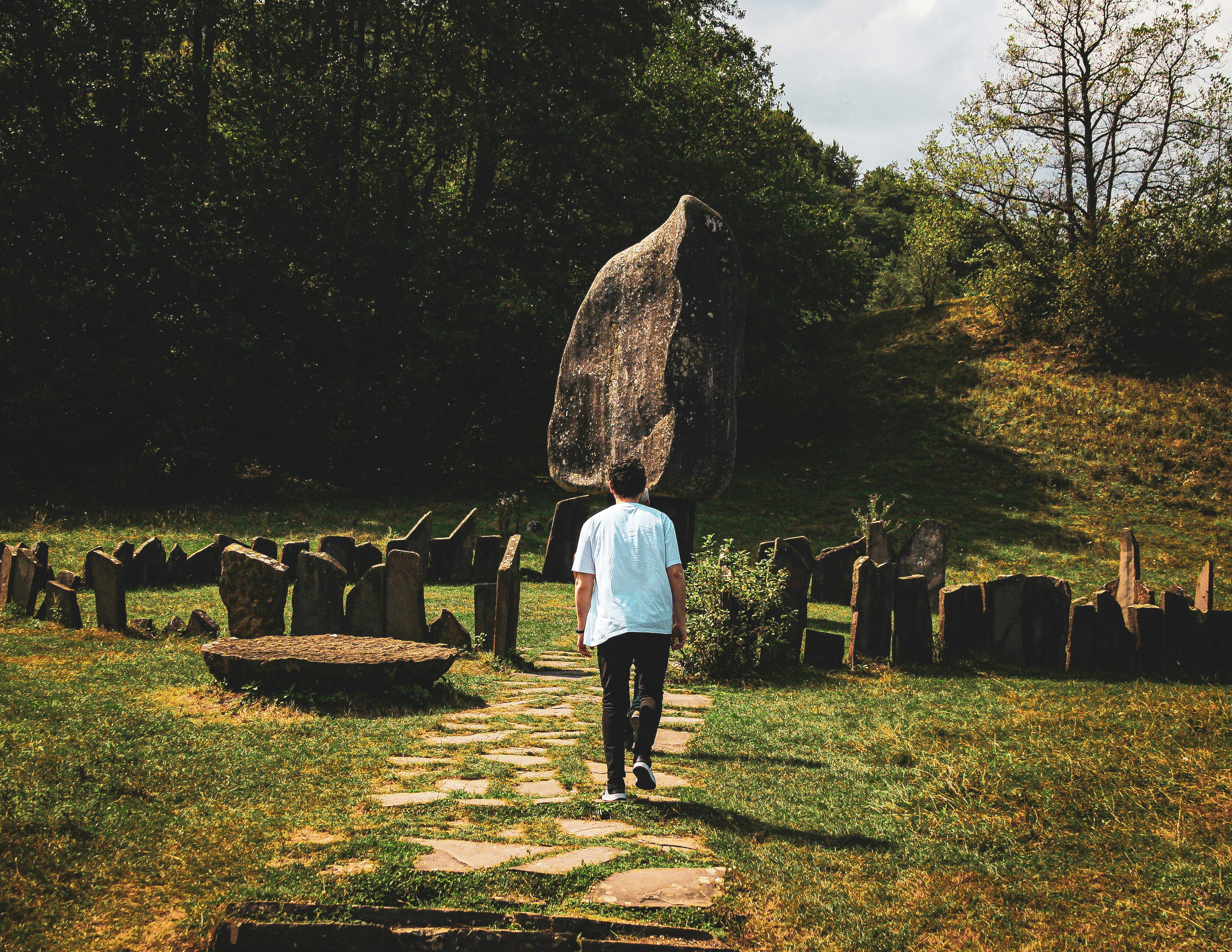 A man walking towards a large rock in a cemetery photo – Free Memorial ...